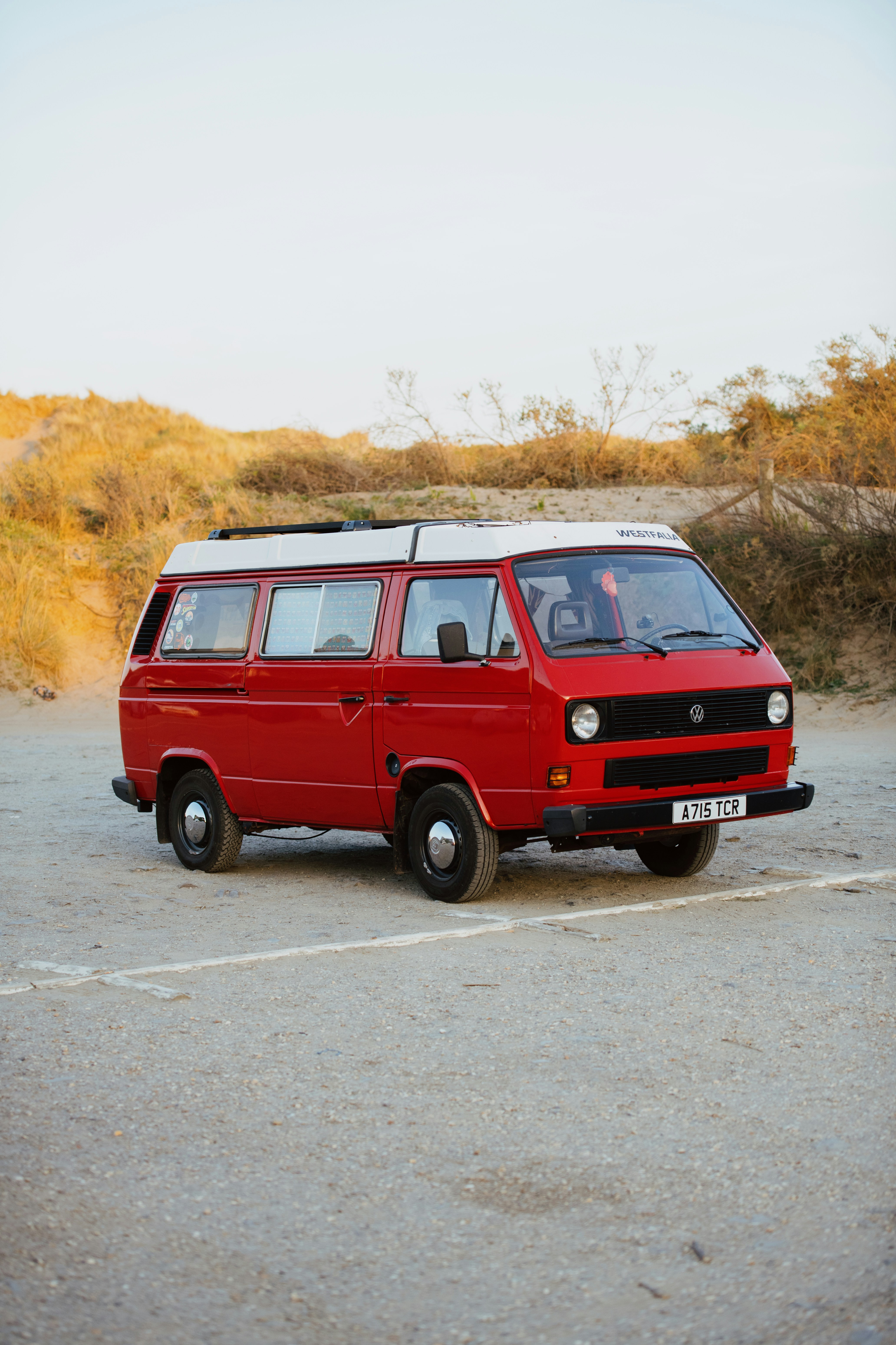 Red vintage volkswagen van parked on gravel