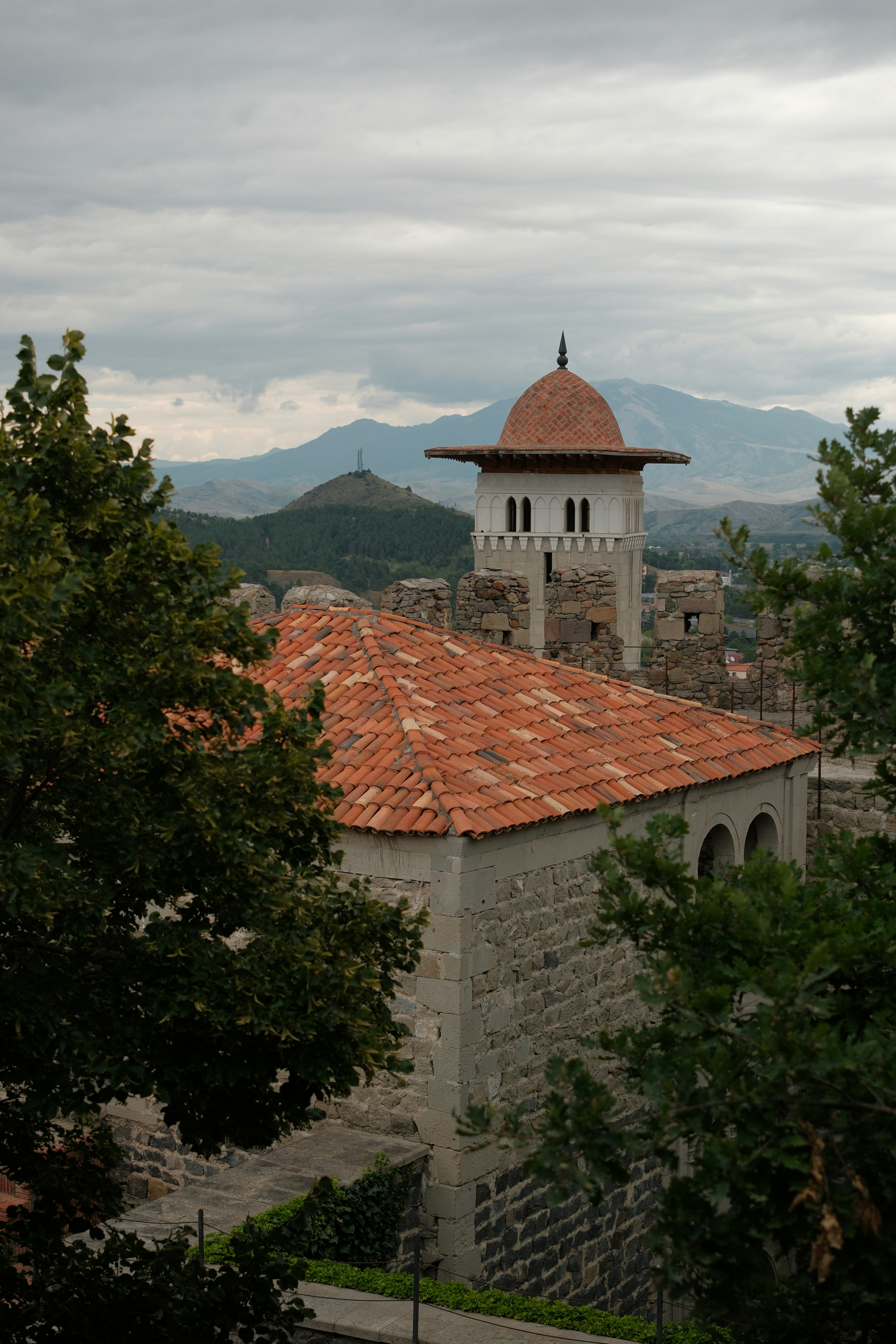 Ancient stone castle with red tiled roofs and tower.