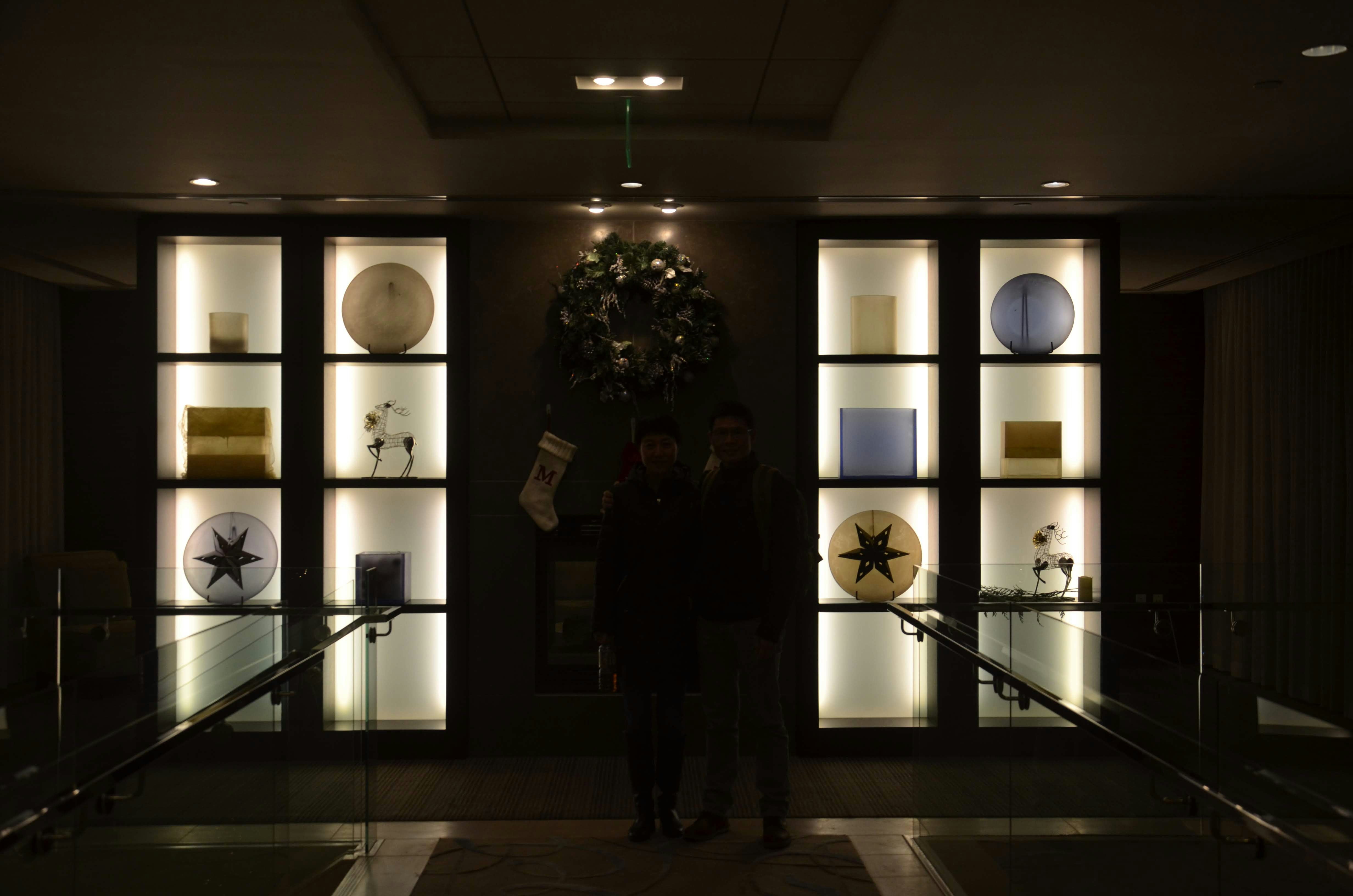 Two people stand in a dimly lit hallway with illuminated displays.