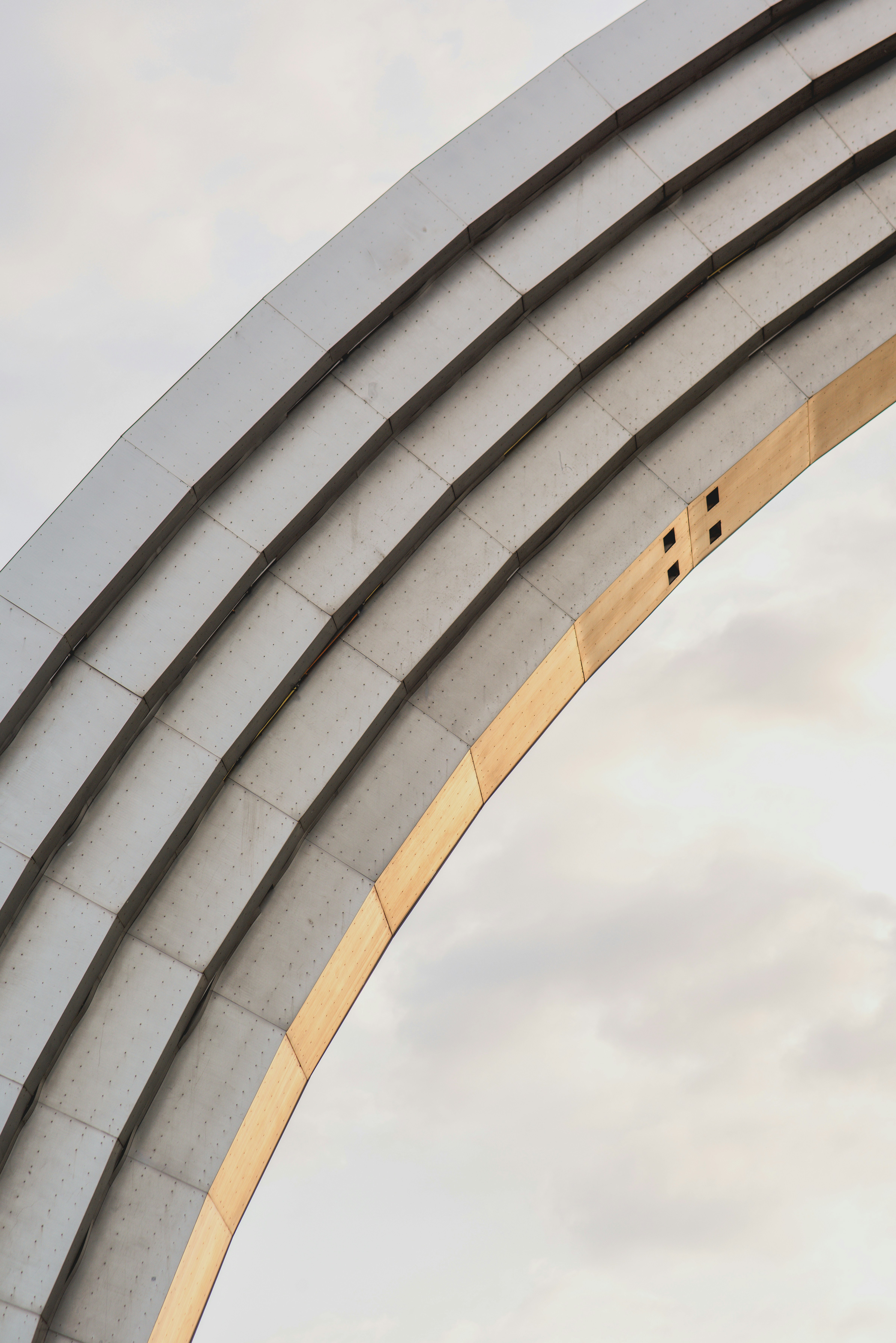 Large metal arch structure against a cloudy sky