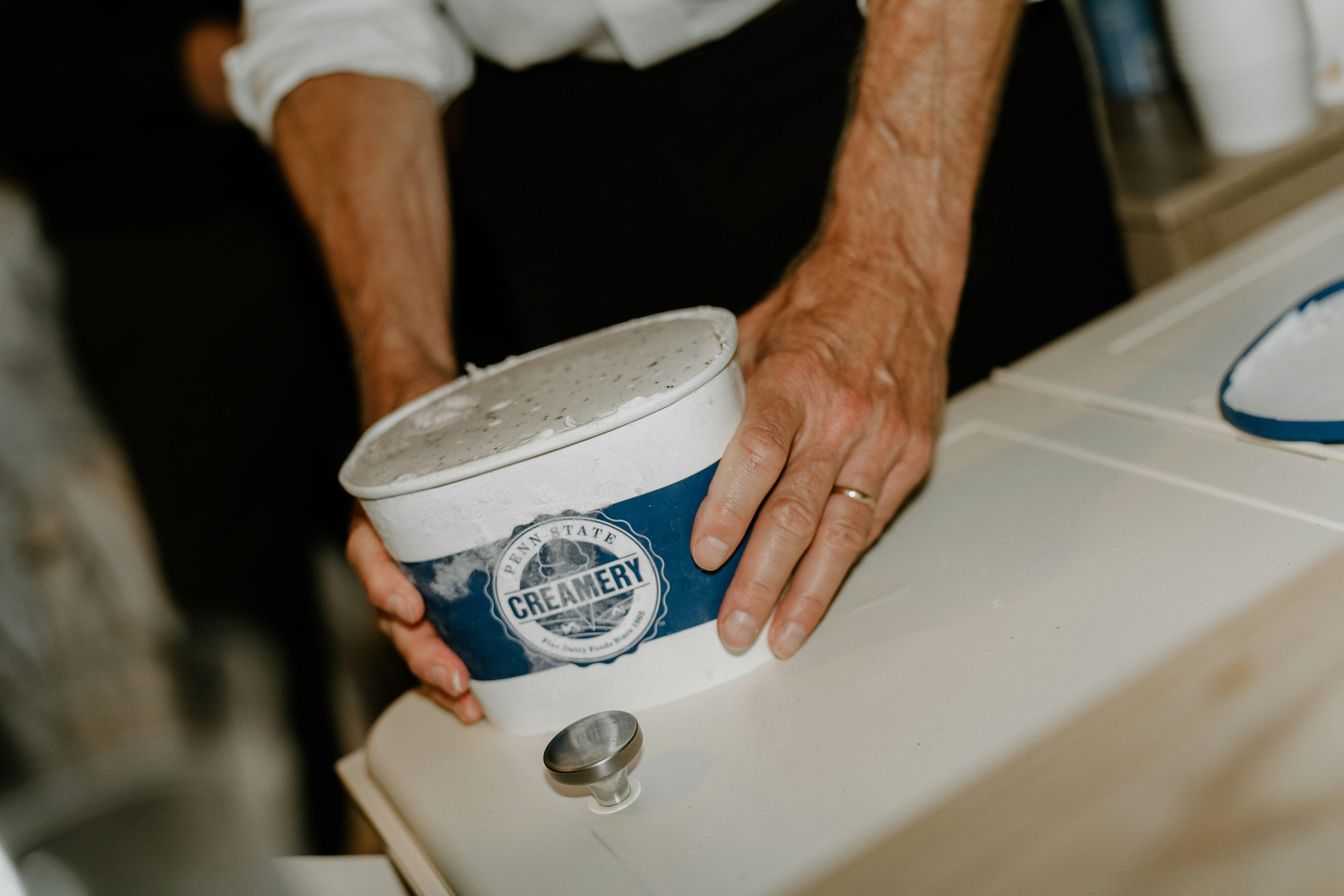 Chilled Creamery Hand: A Close-Up of a Hand Gripping a Pail in the Dairy Counter