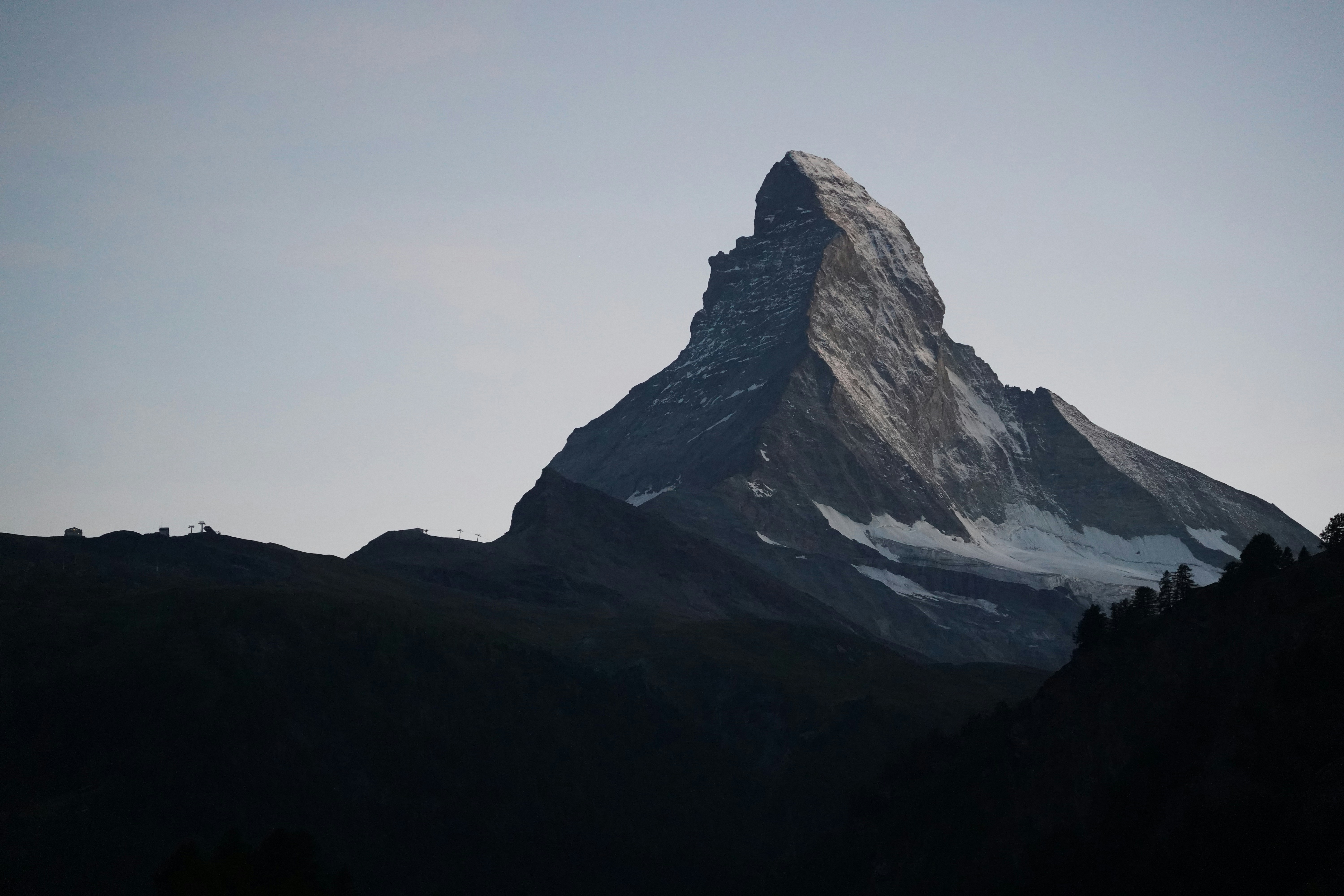 Majestic mountain peak rising against a twilight sky, showcasing its rugged silhouette and snow-capped summit.