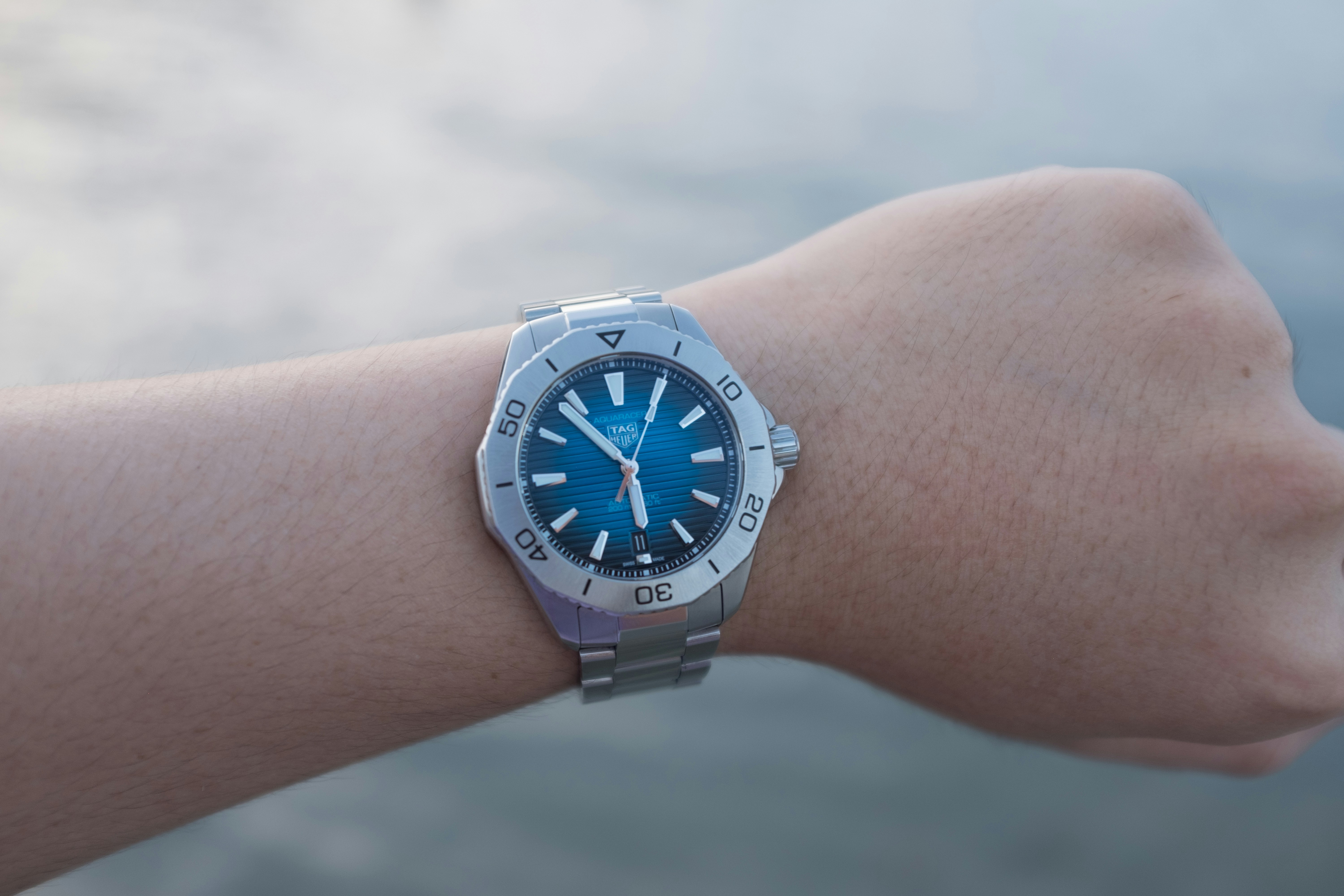 Person wearing a silver watch with blue face.