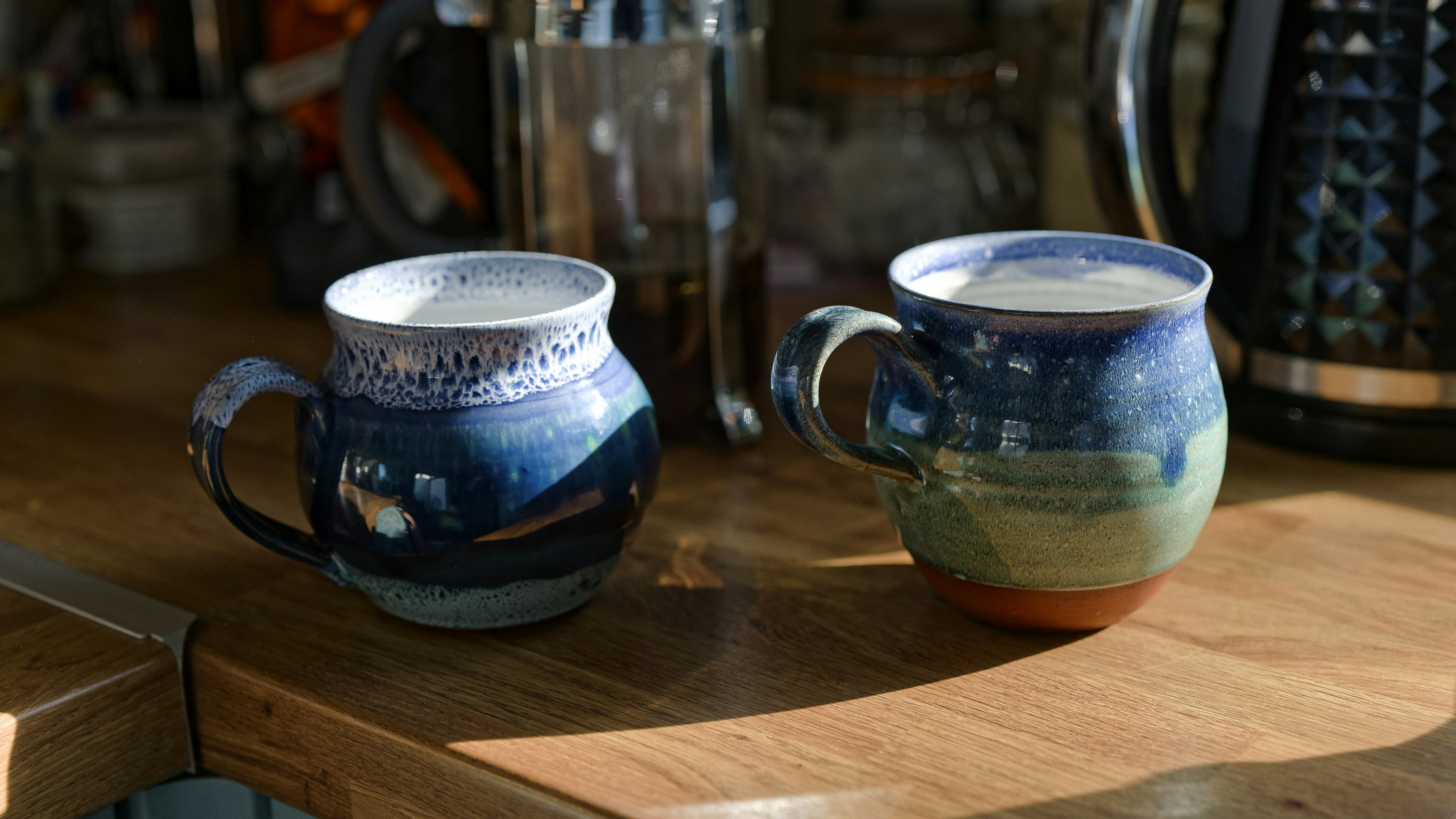 Hand crafted mugs | Two colorful ceramic mugs on a wooden surface