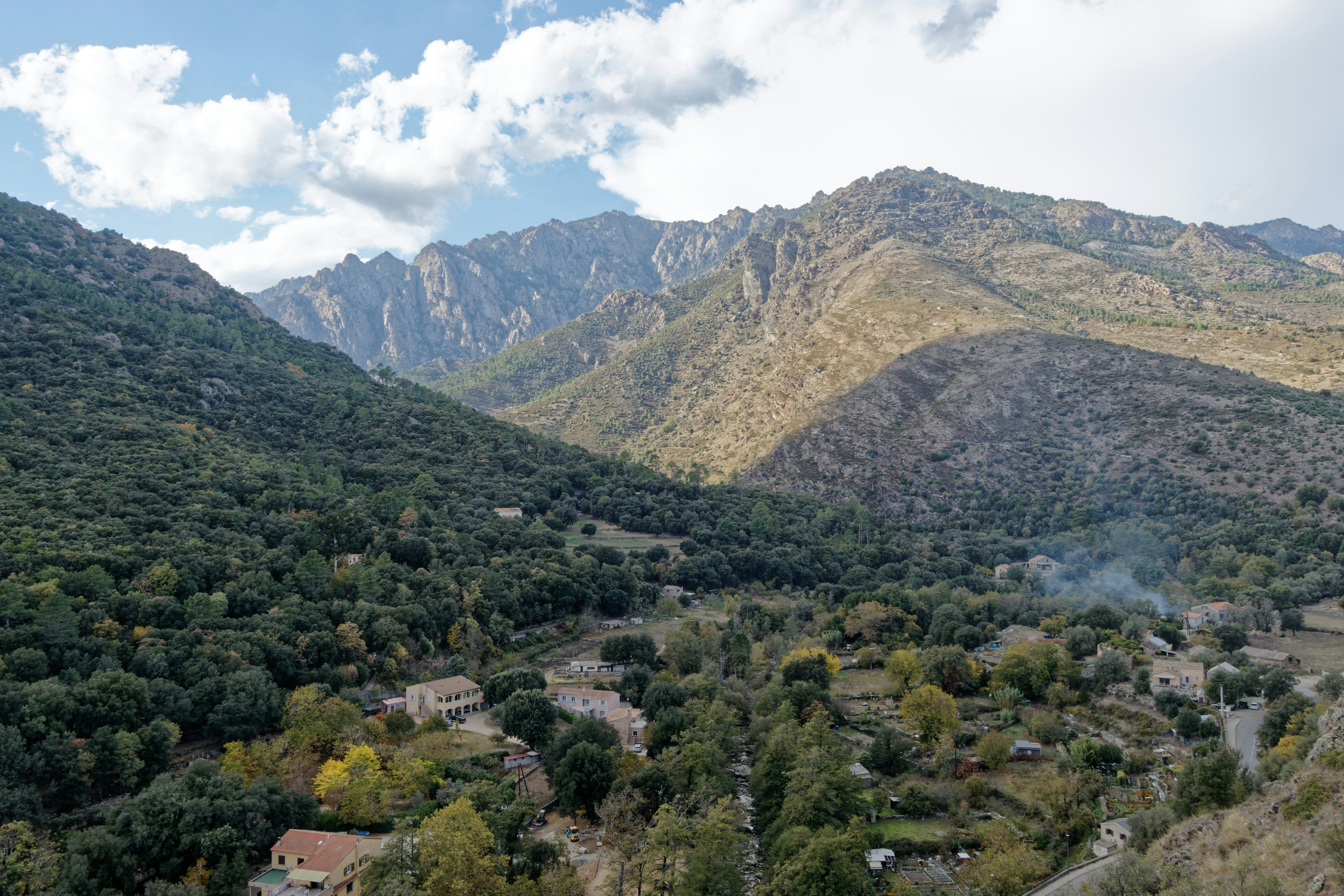 Green valley with scattered houses and rocky mountains.