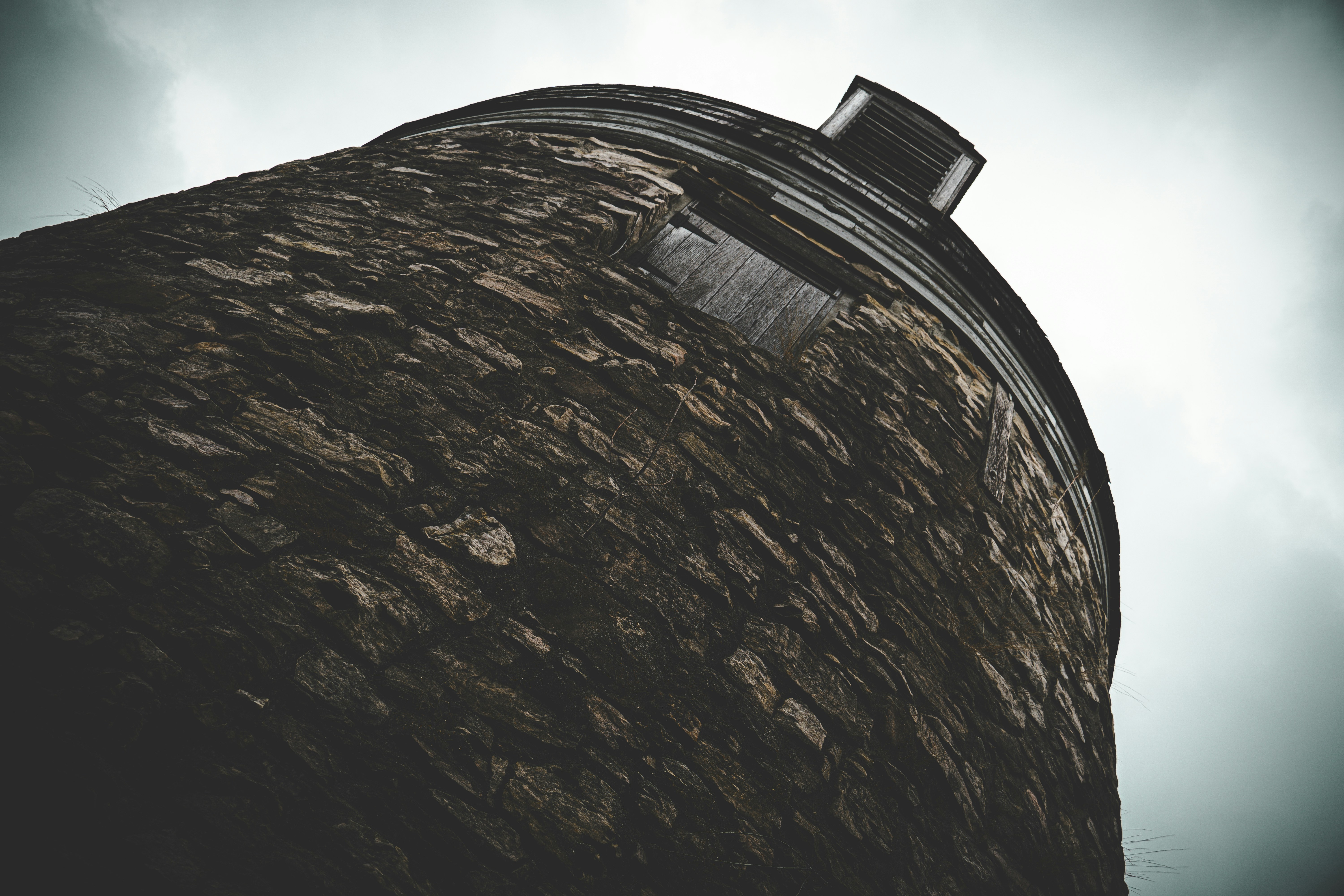 Stone tower viewed from below against cloudy sky