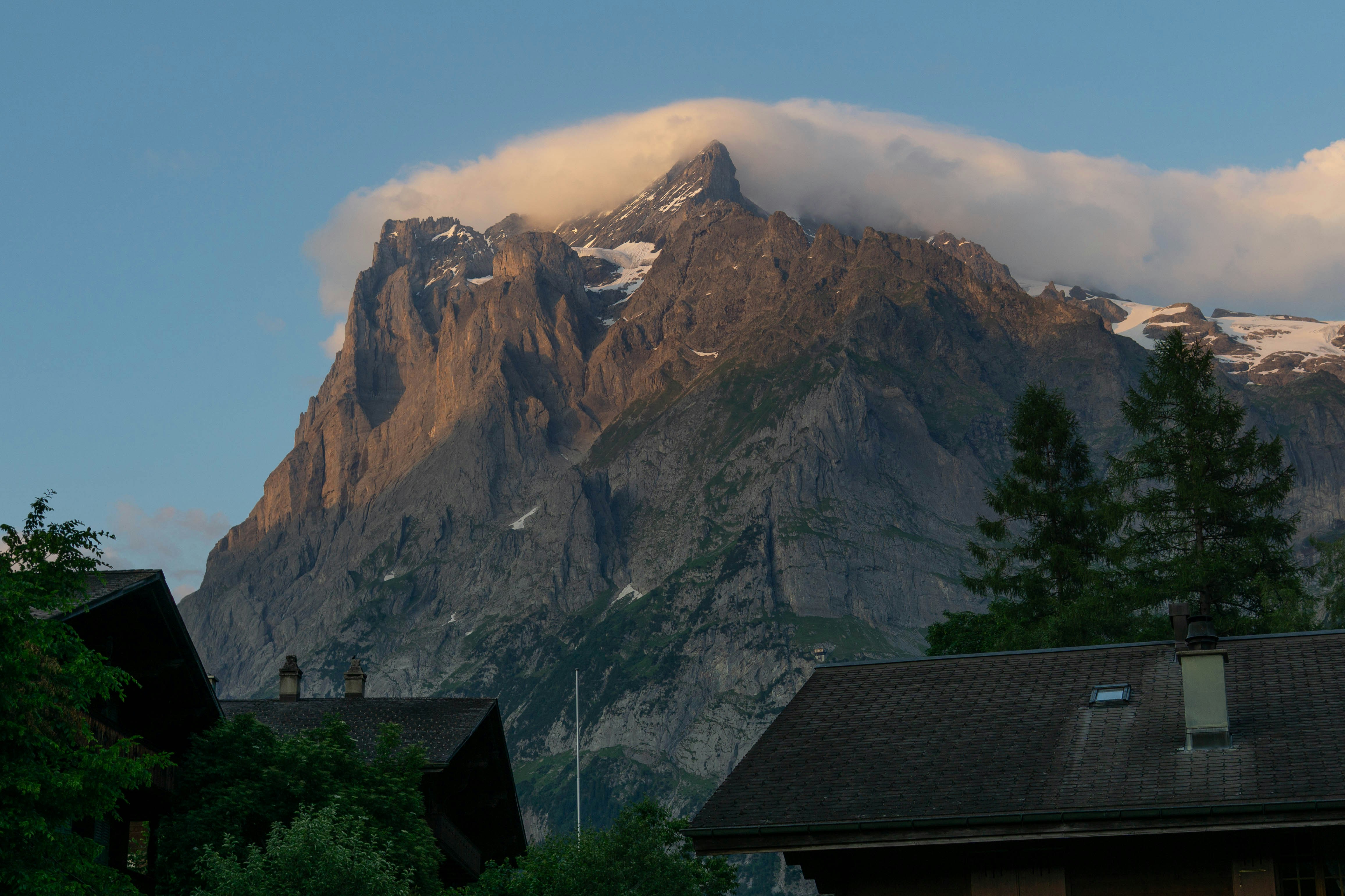 Sunset with clouds caressing a mountain. | Majestic mountain peak shrouded in clouds at sunset