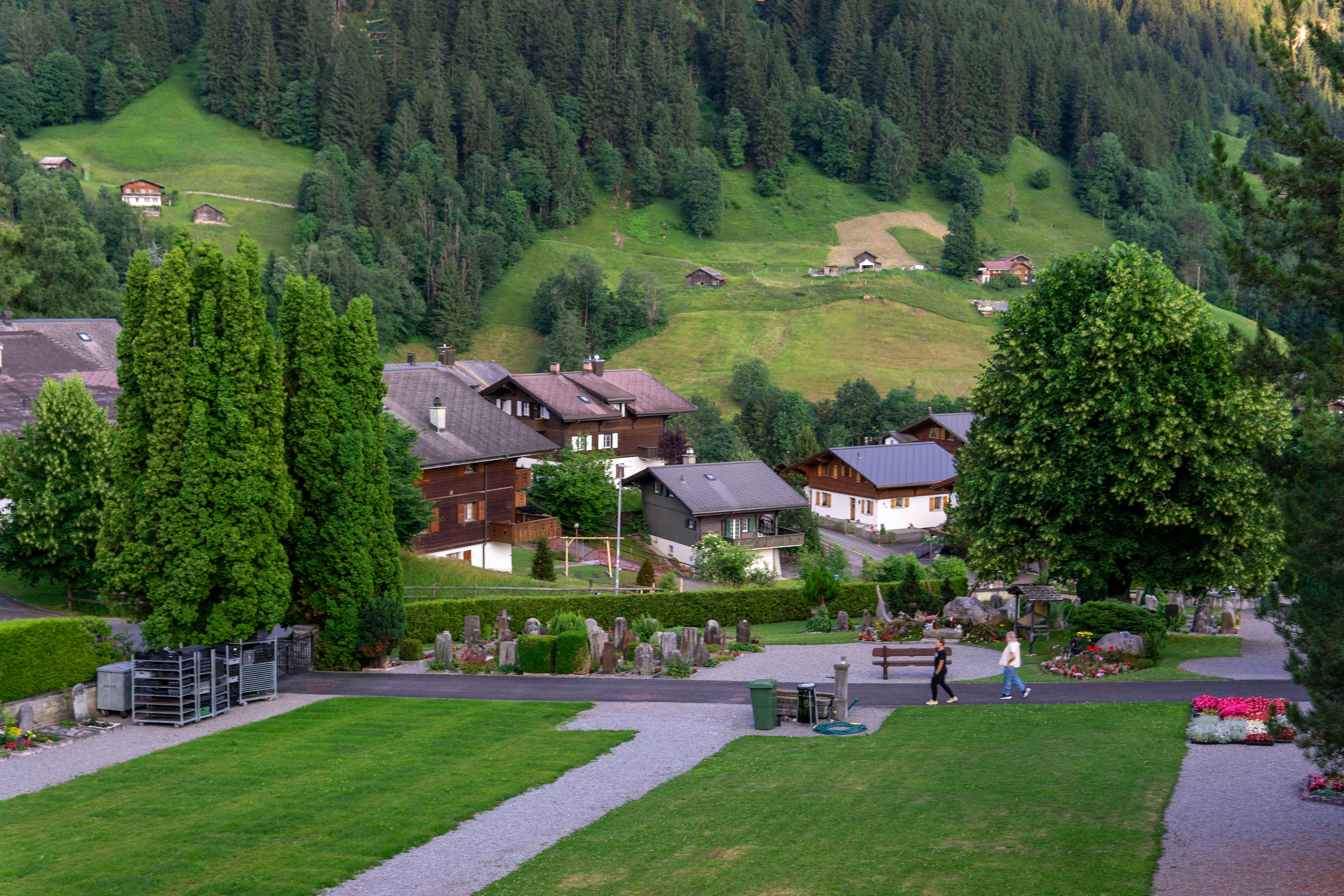 Alpine village nestled in a green valley with mountains.