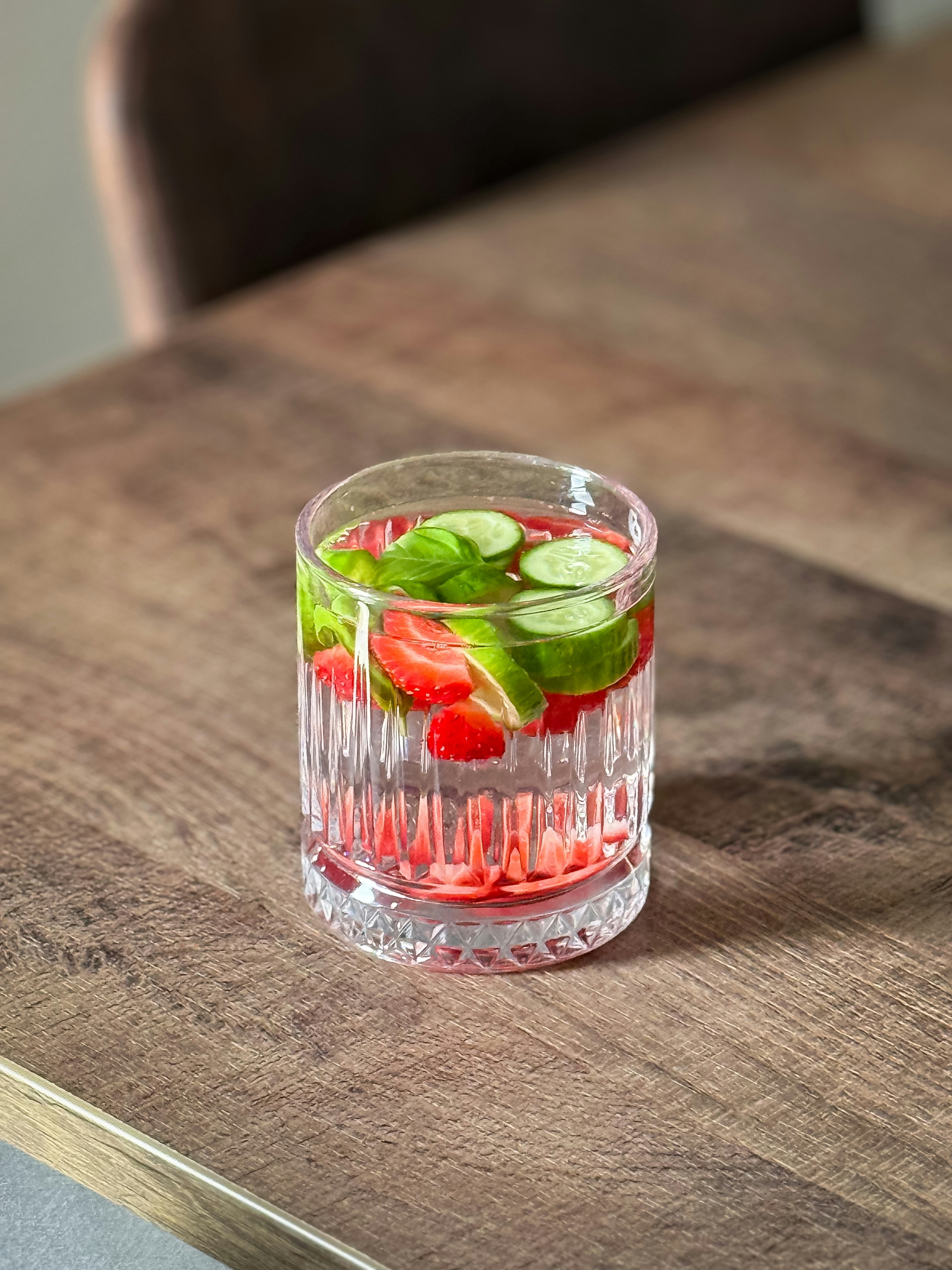 Glass of water with strawberries, cucumber, and mint