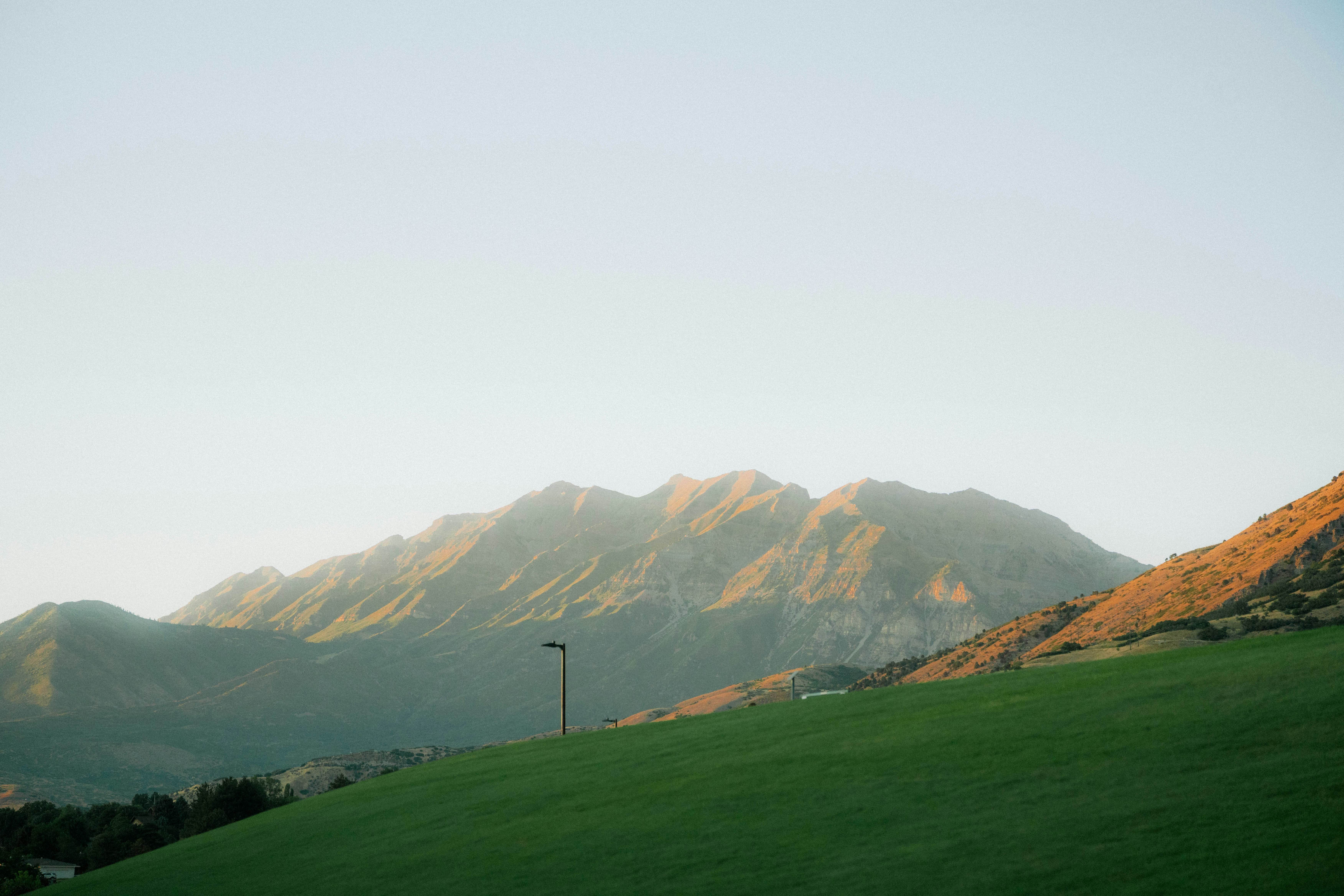 Green grassy hill slopes towards distant sunlit mountains