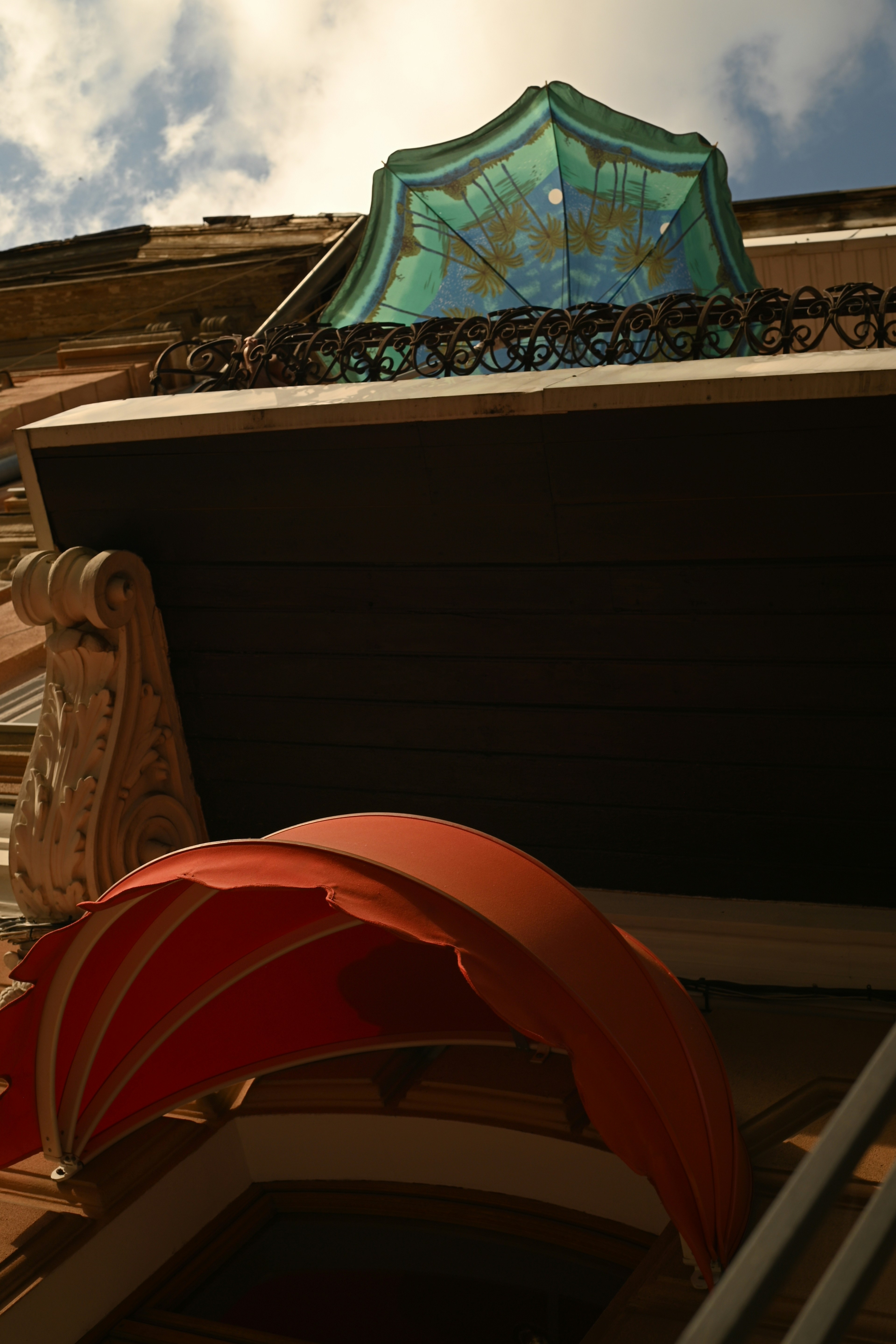 Teal parasol perched above a wrought-iron balcony on a sun-drenched rooftop