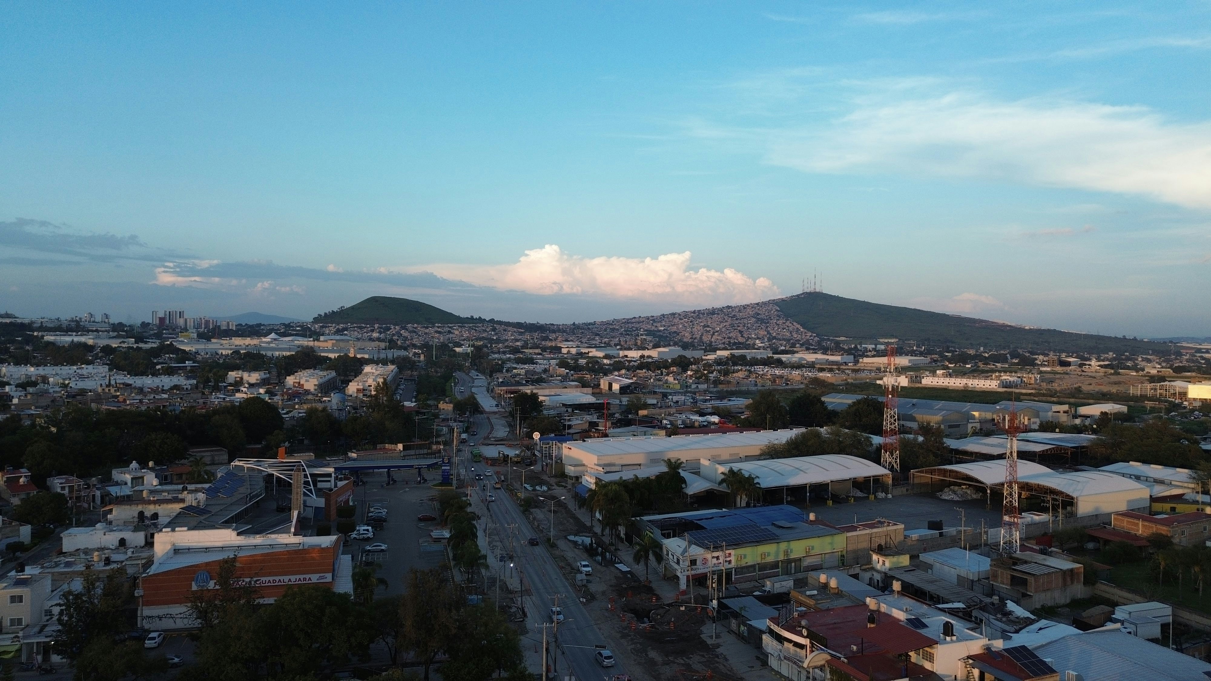 Paisaje de una avenida en reparación, al atardecer. | Aerial view of a city street leading to mountains