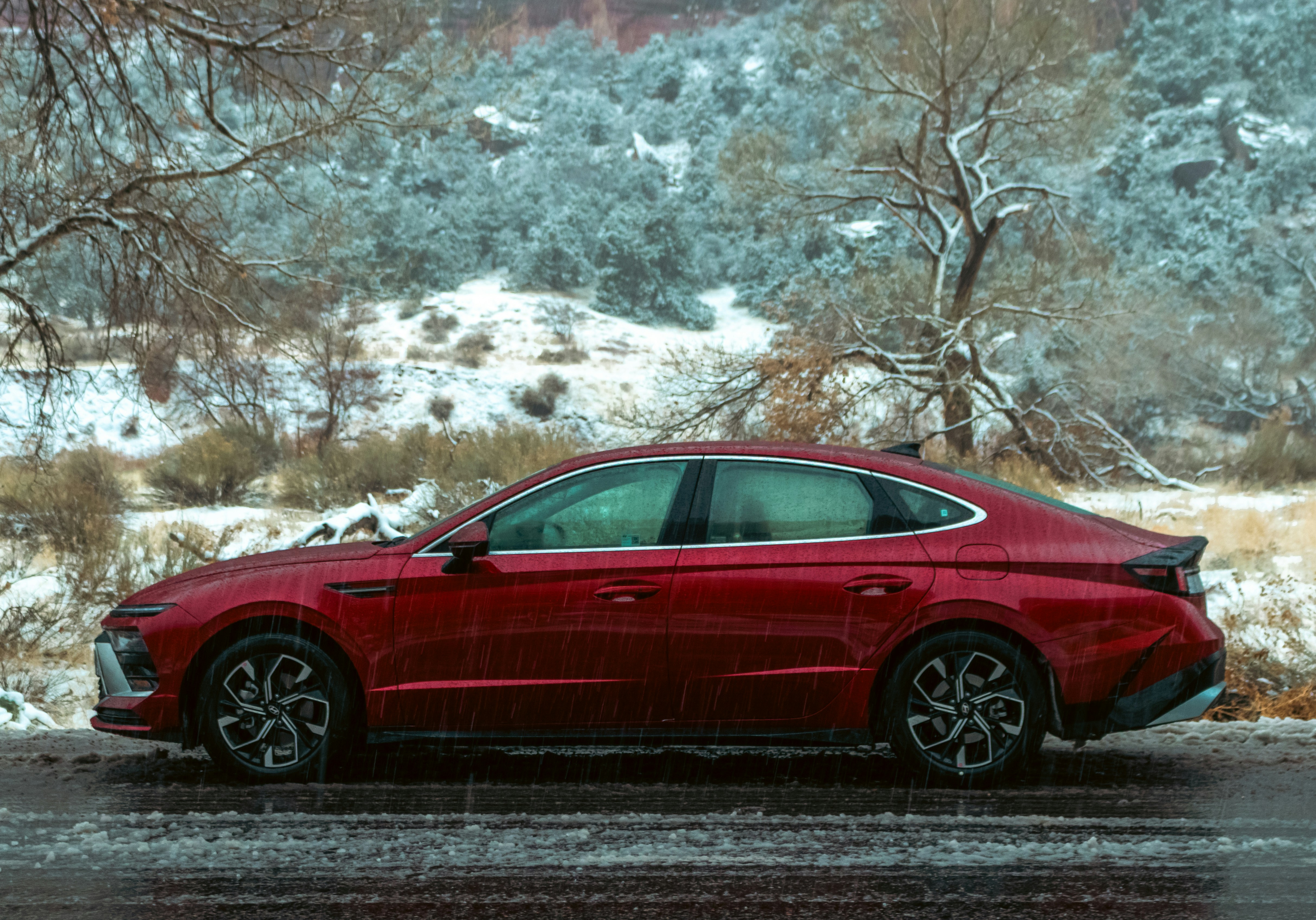 A Red Hyundai Sonata is parked on the side of the road in Zion National Park on a cold winter day in February 2025. | Red car parked on a snowy road