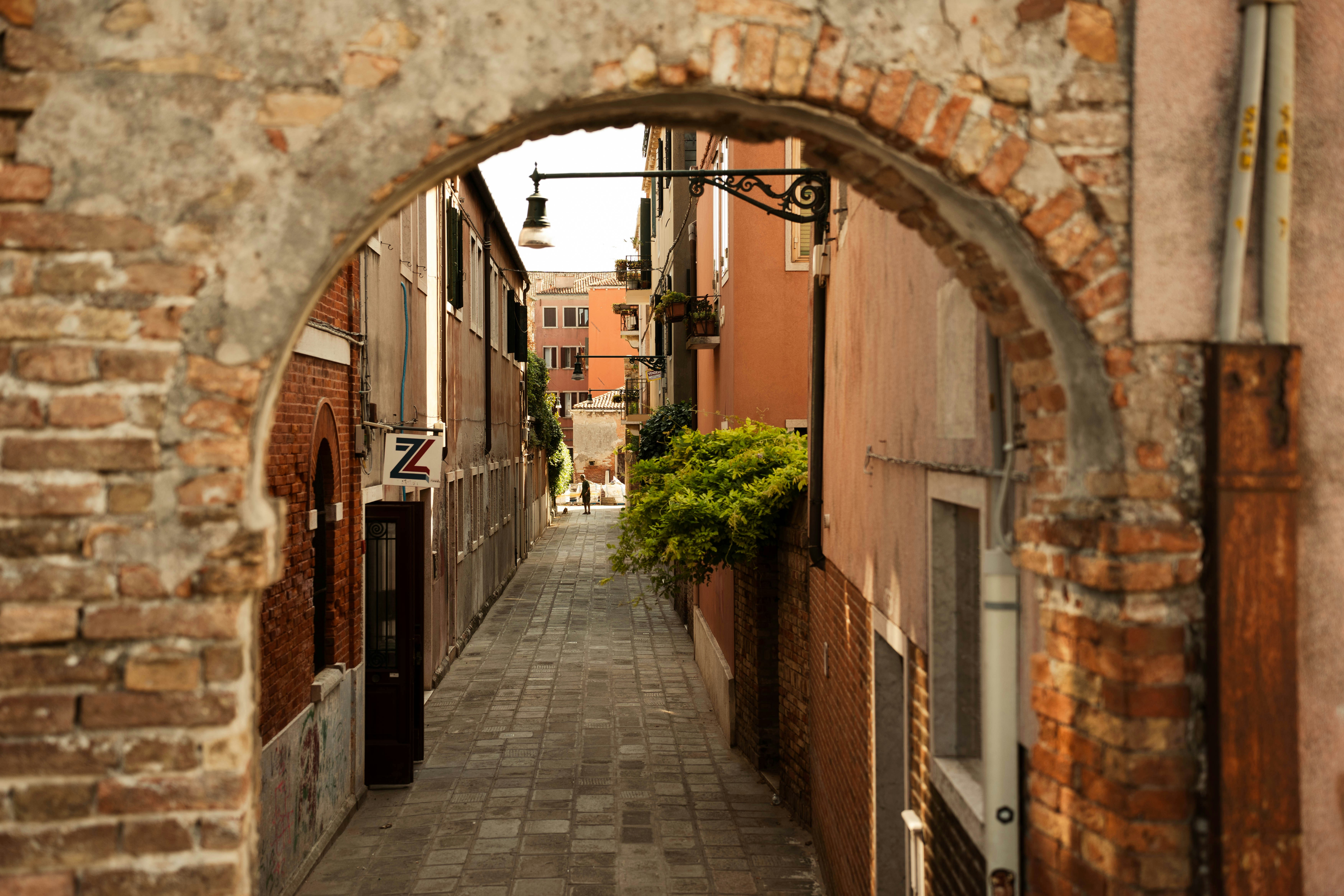 Narrow venetian alleyway seen through brick archway