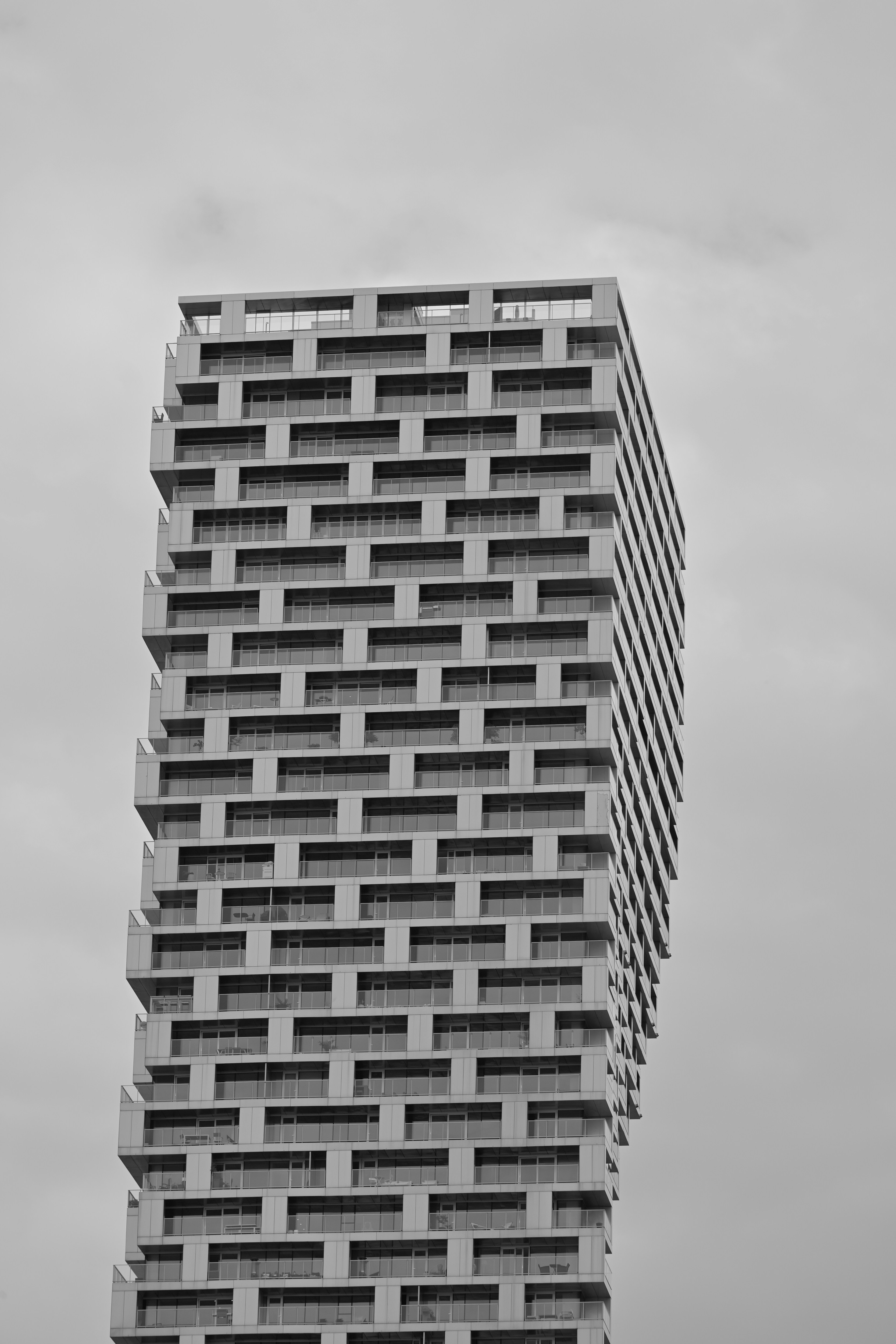 Modern skyscraper with balconies against cloudy sky