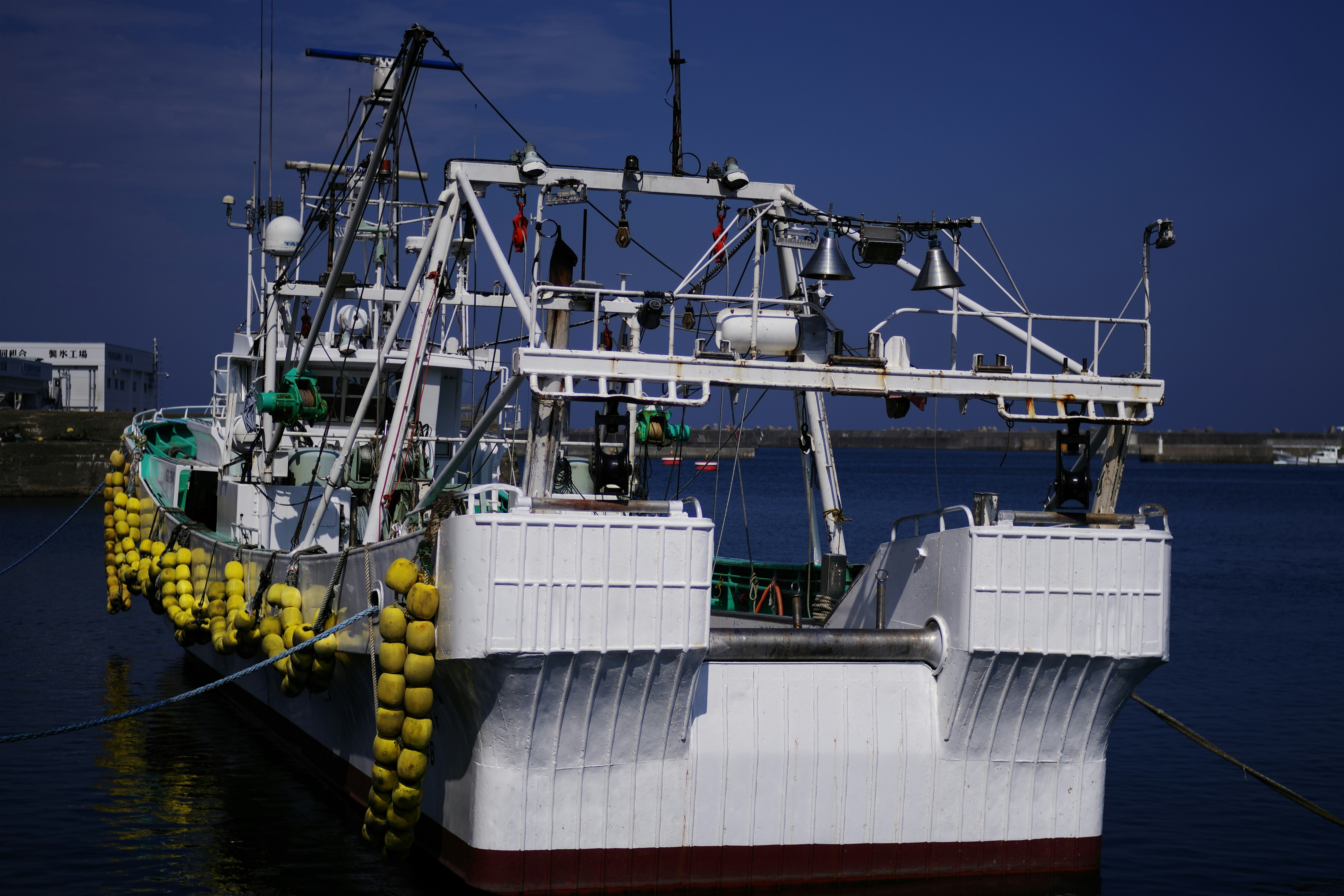Fishing trawler docked in harbor under clear blue sky