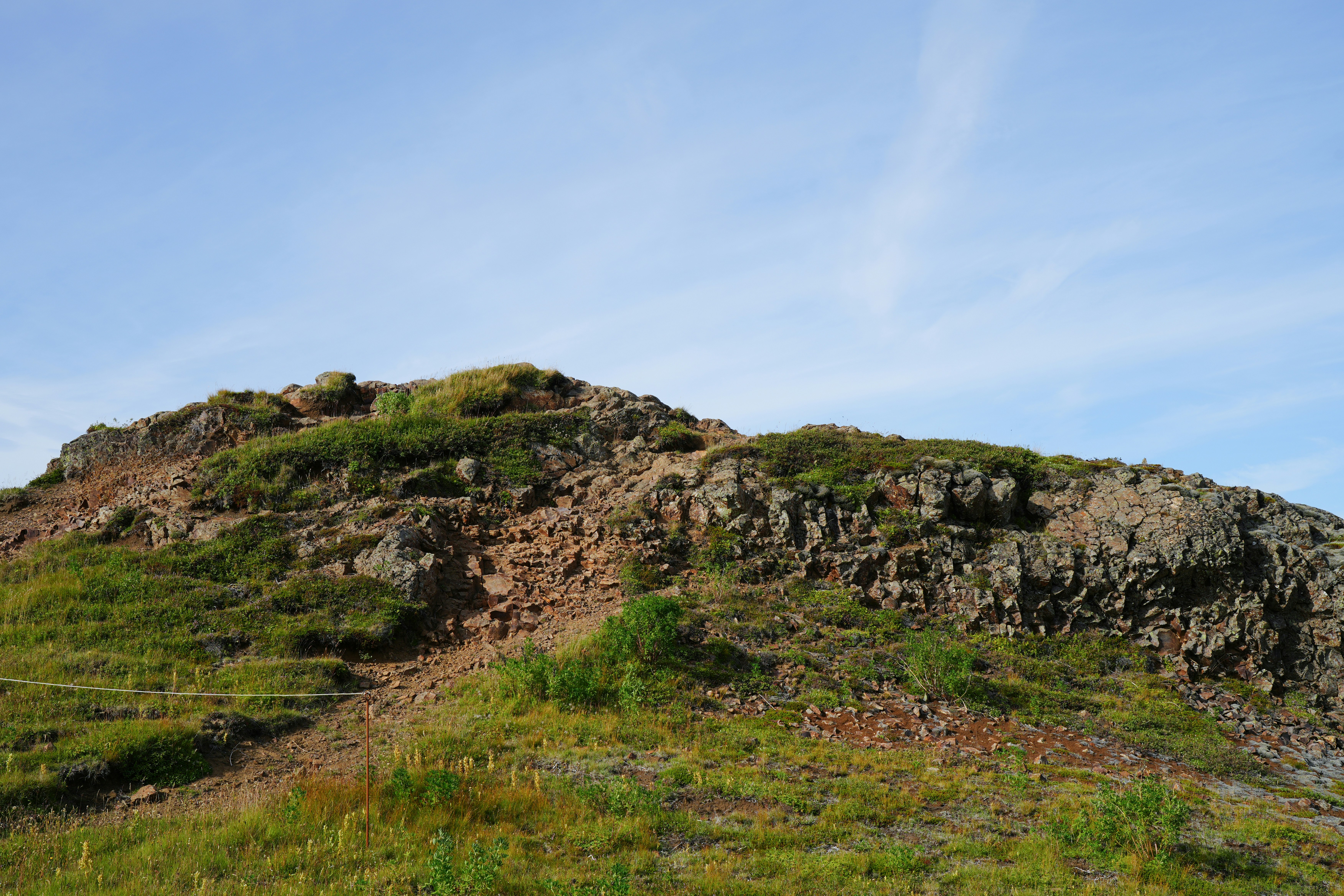 Rocky hill with green grass and blue sky