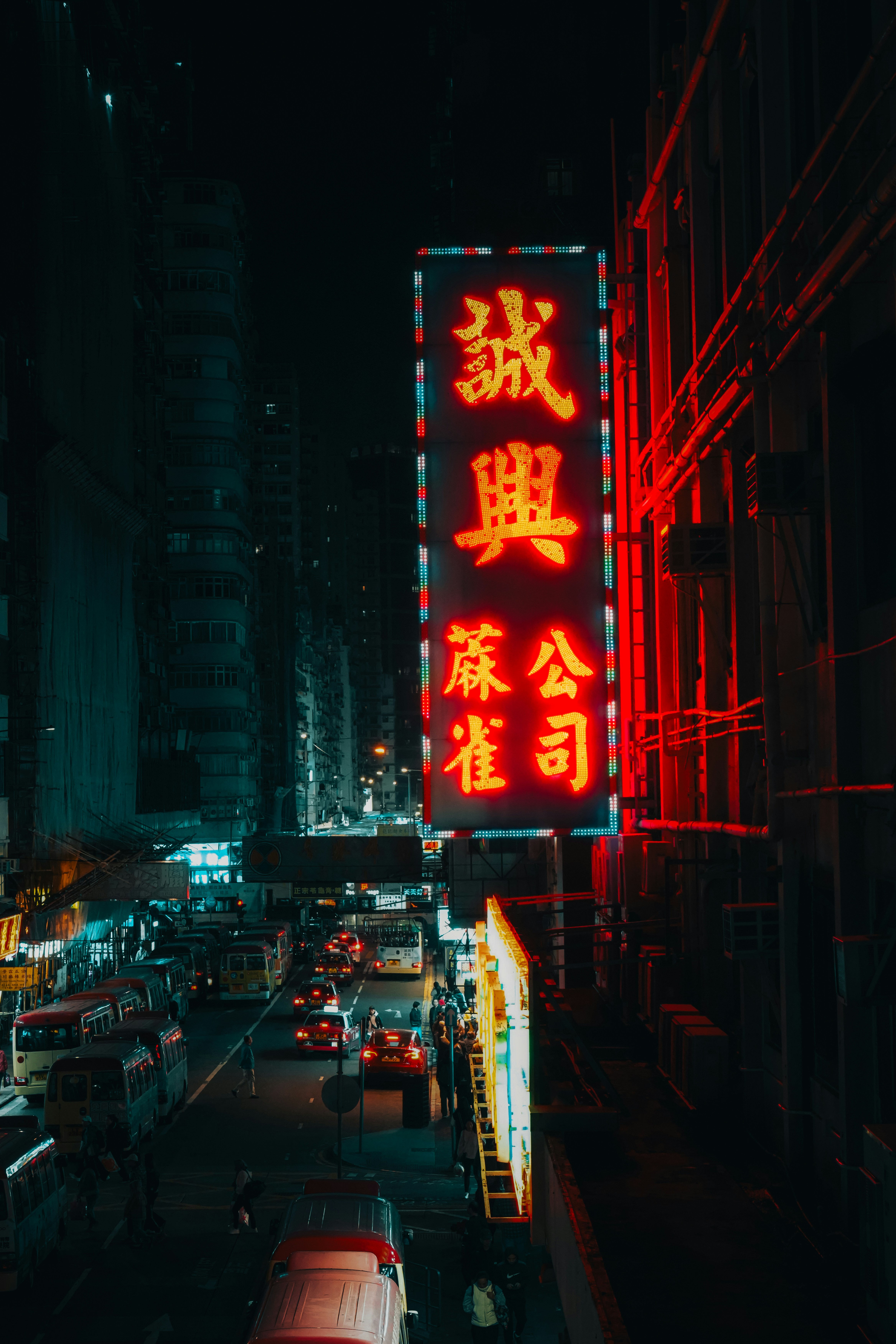 Hong Kong Street View - Sun Hung | Neon sign illuminates a busy city street at night.
