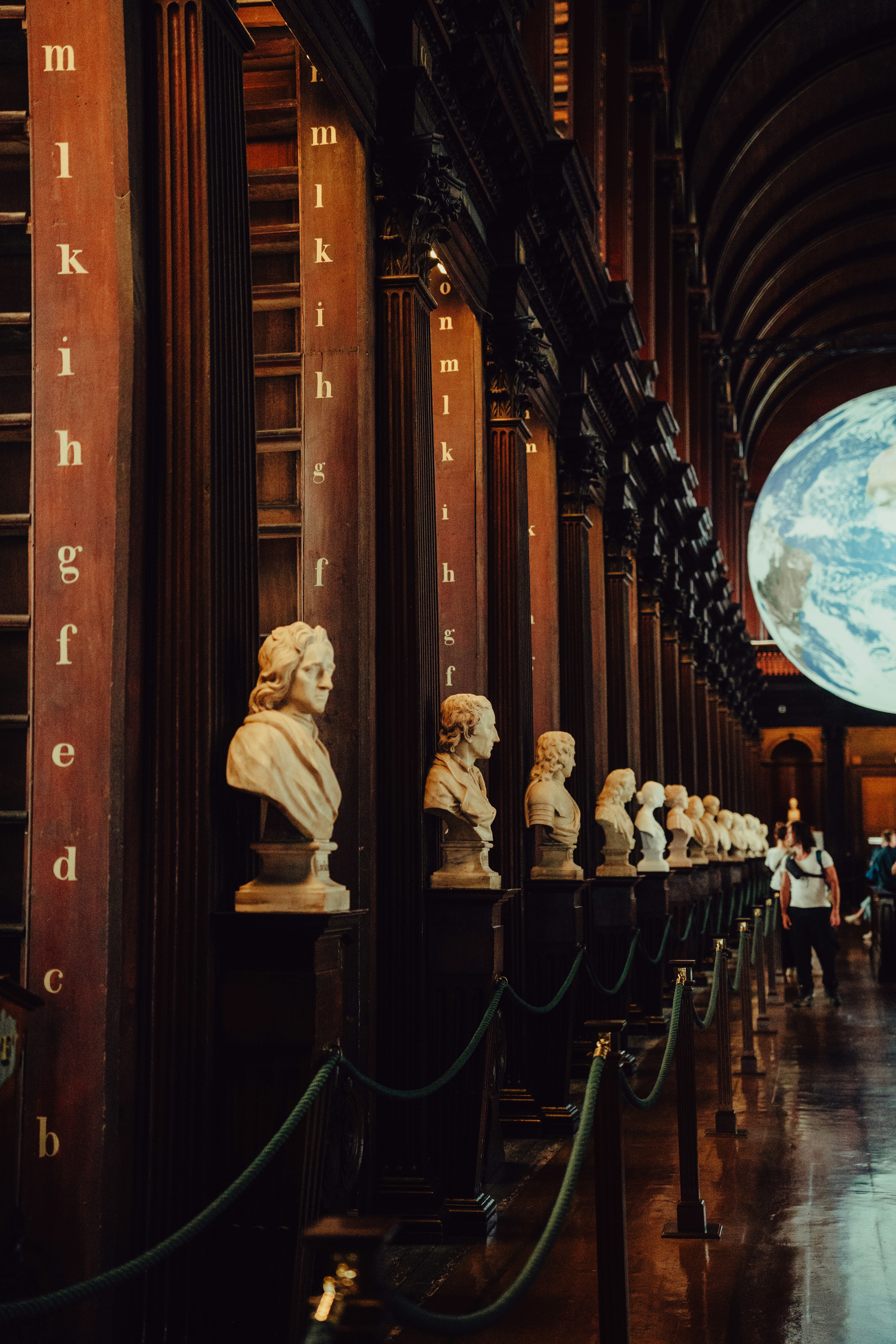 Marble busts line a library aisle with a globe overhead photo – Free ...