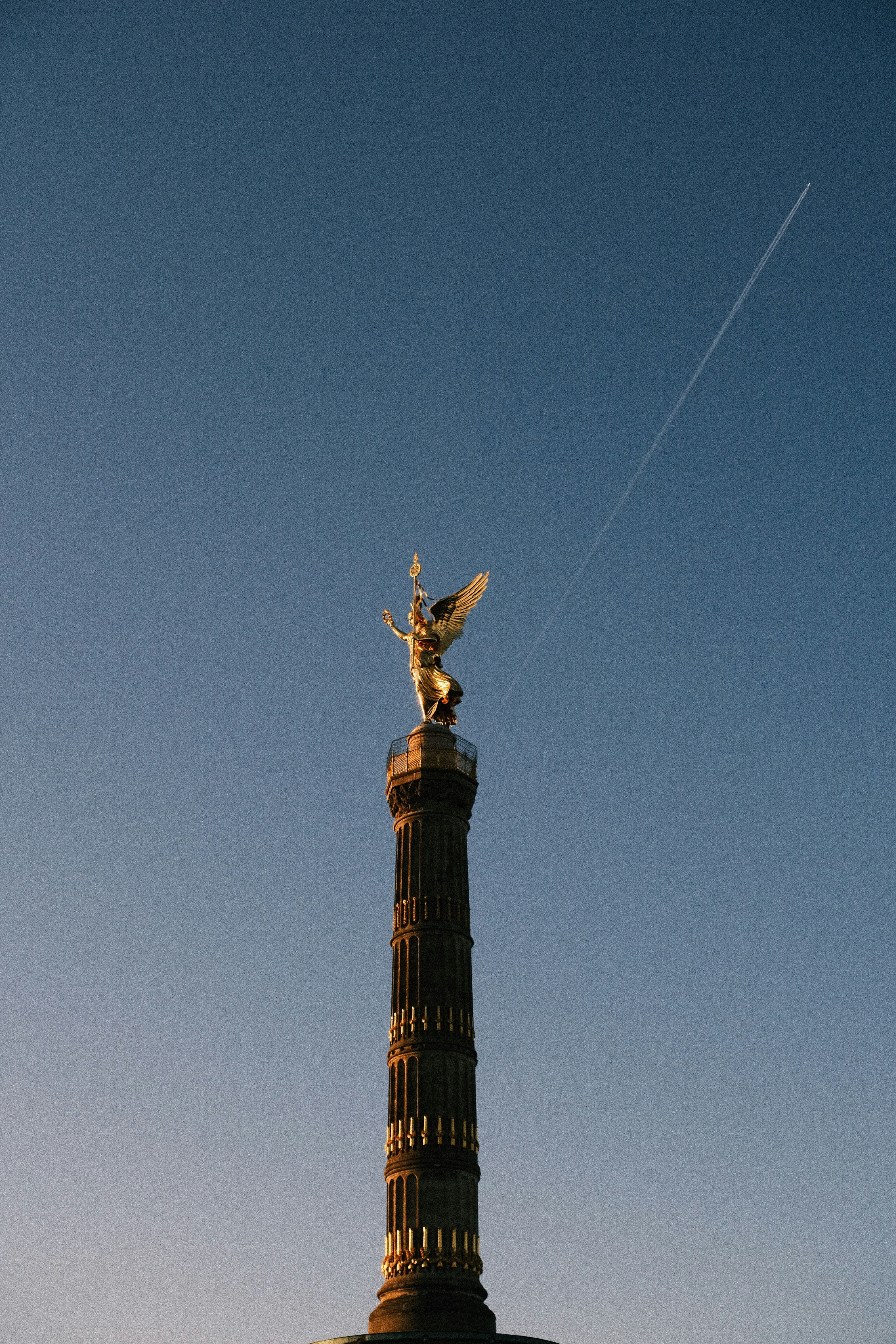 Golden angel statue atop tall column against clear sky