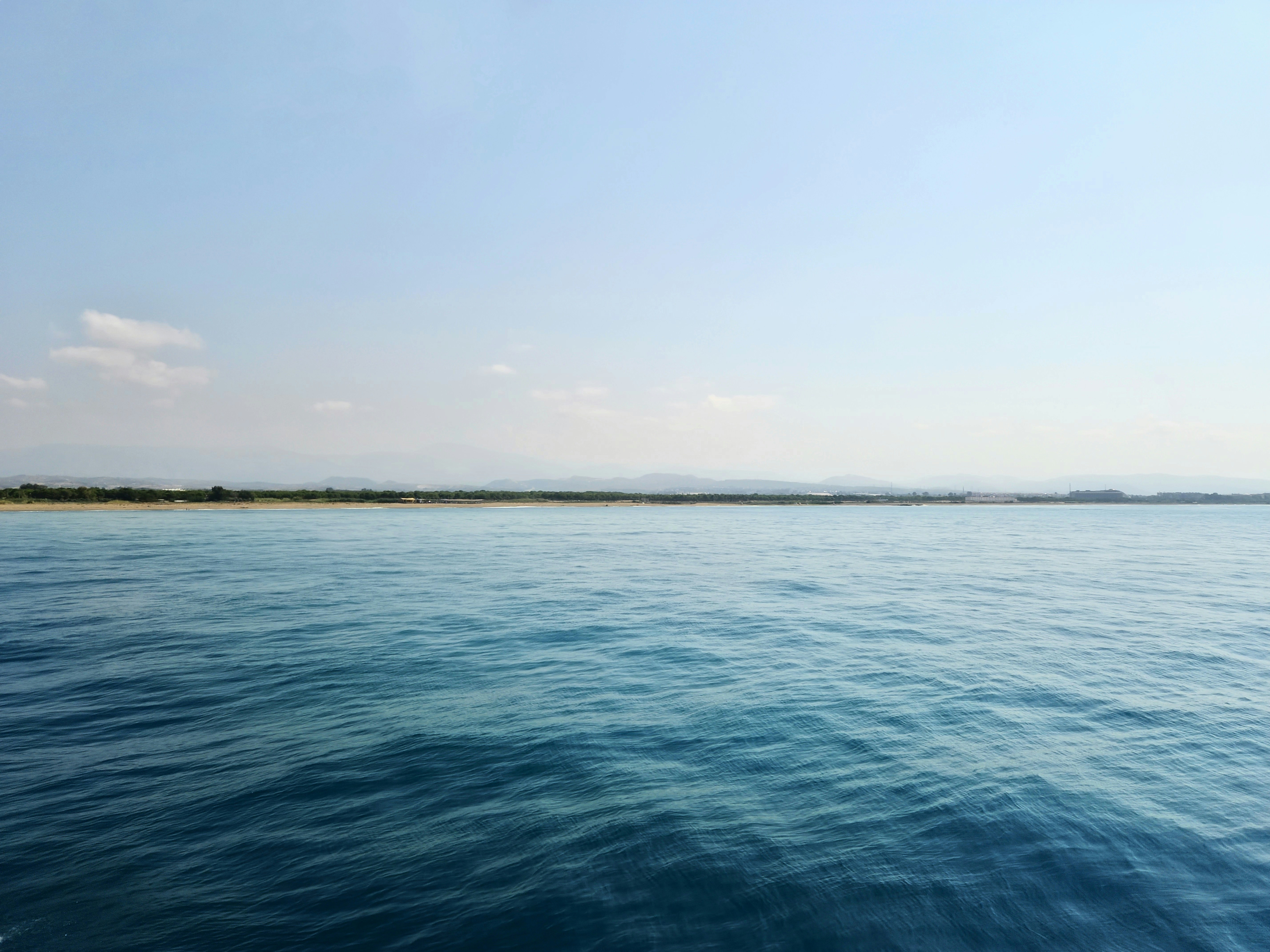 Calm blue ocean water with distant shoreline underpopulated shoreline