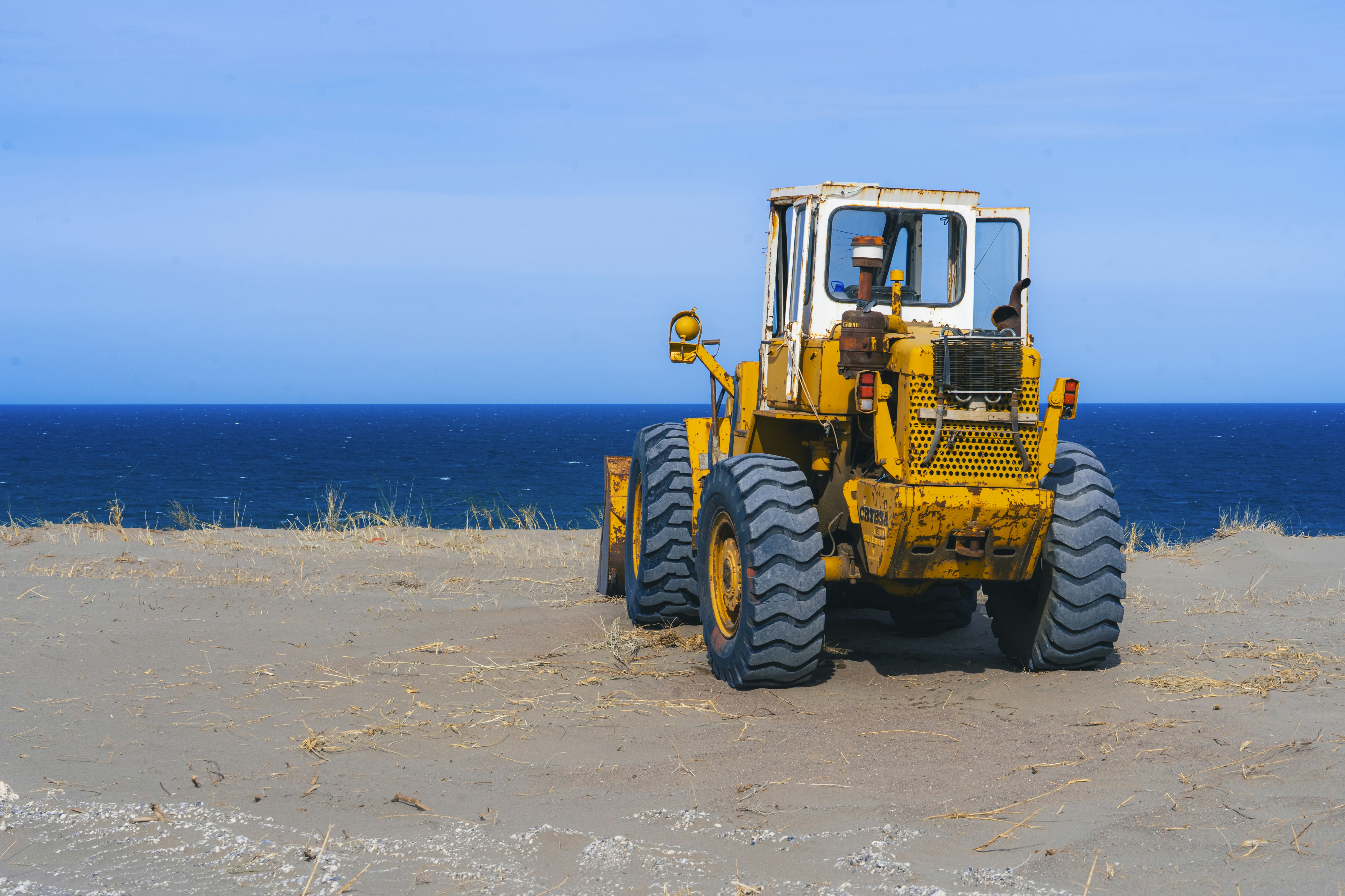 Yellow front loader parked on a sandy beach
