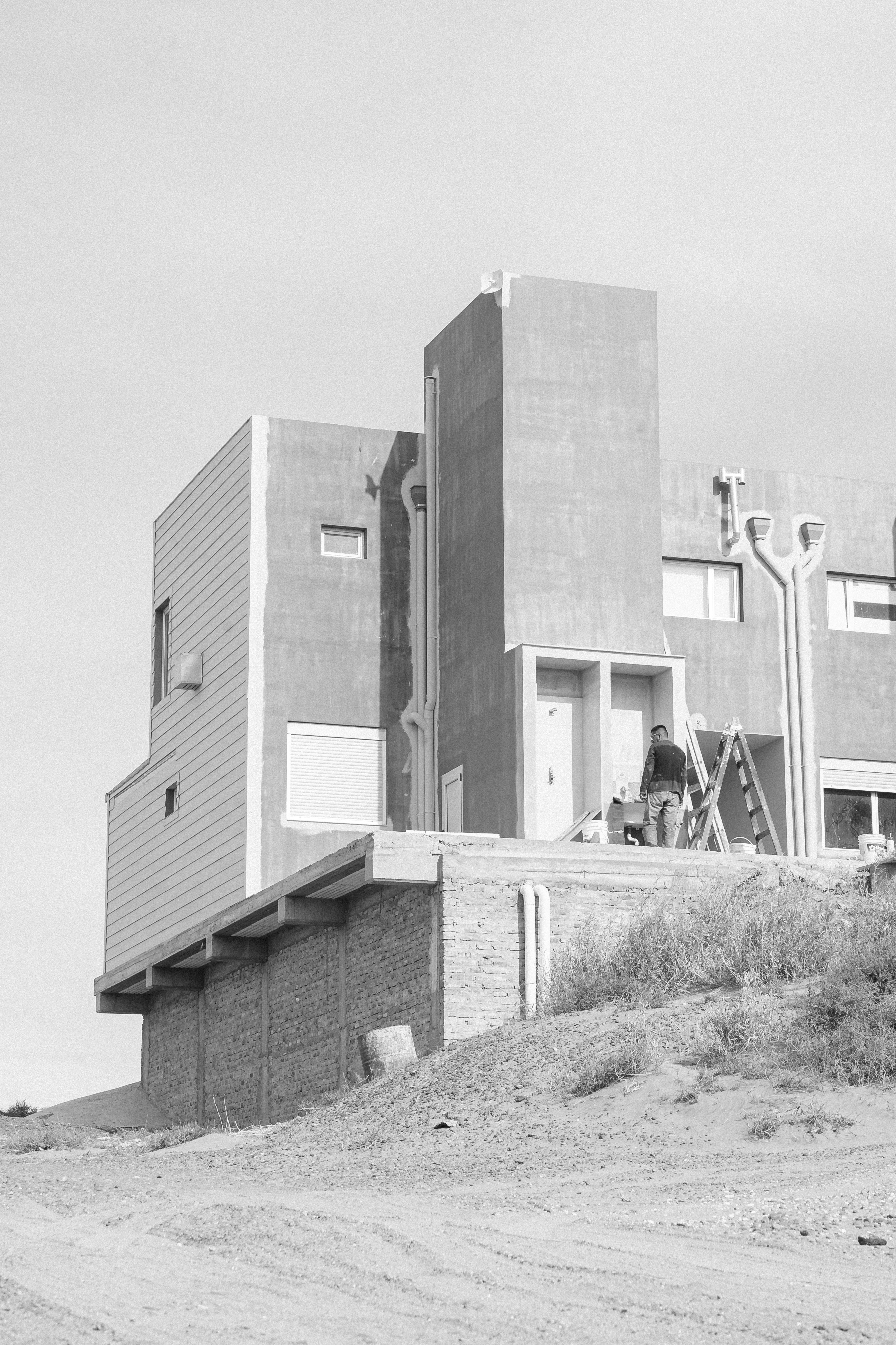 Man painting a modern building exterior on a ladder