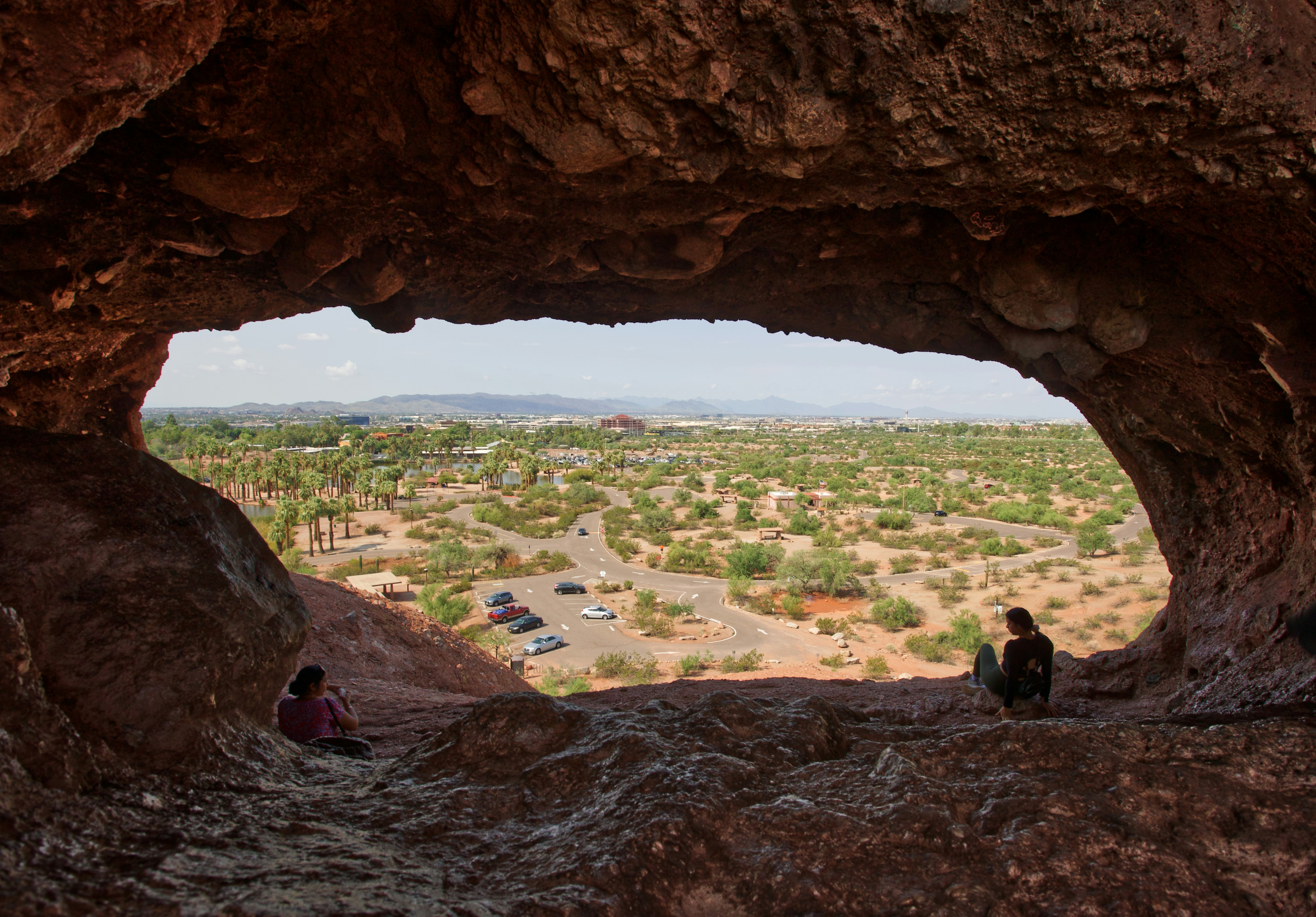 Two people in a cave overlooking a desert landscape.