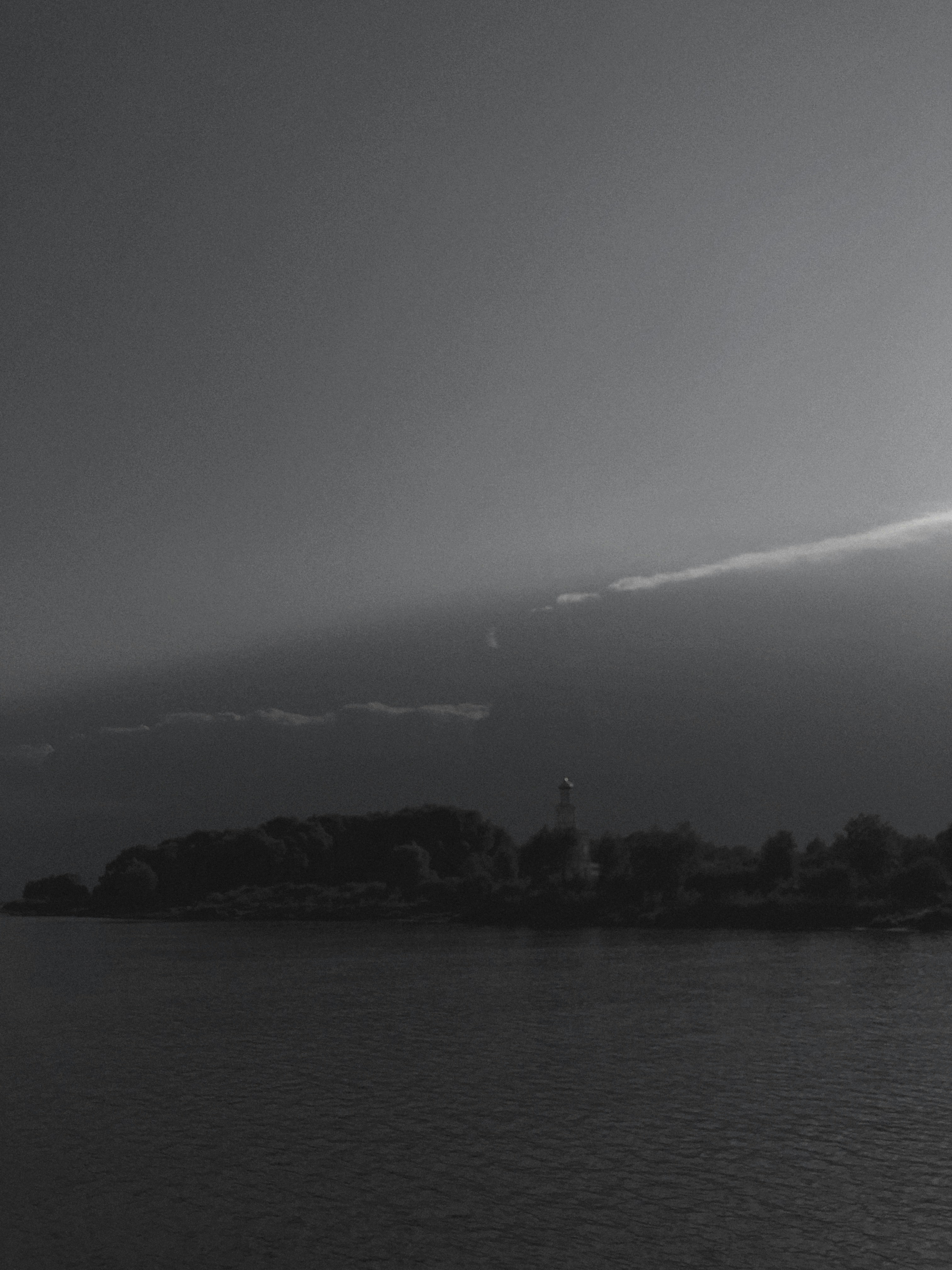 Lighthouse on a distant island under a cloudy sky