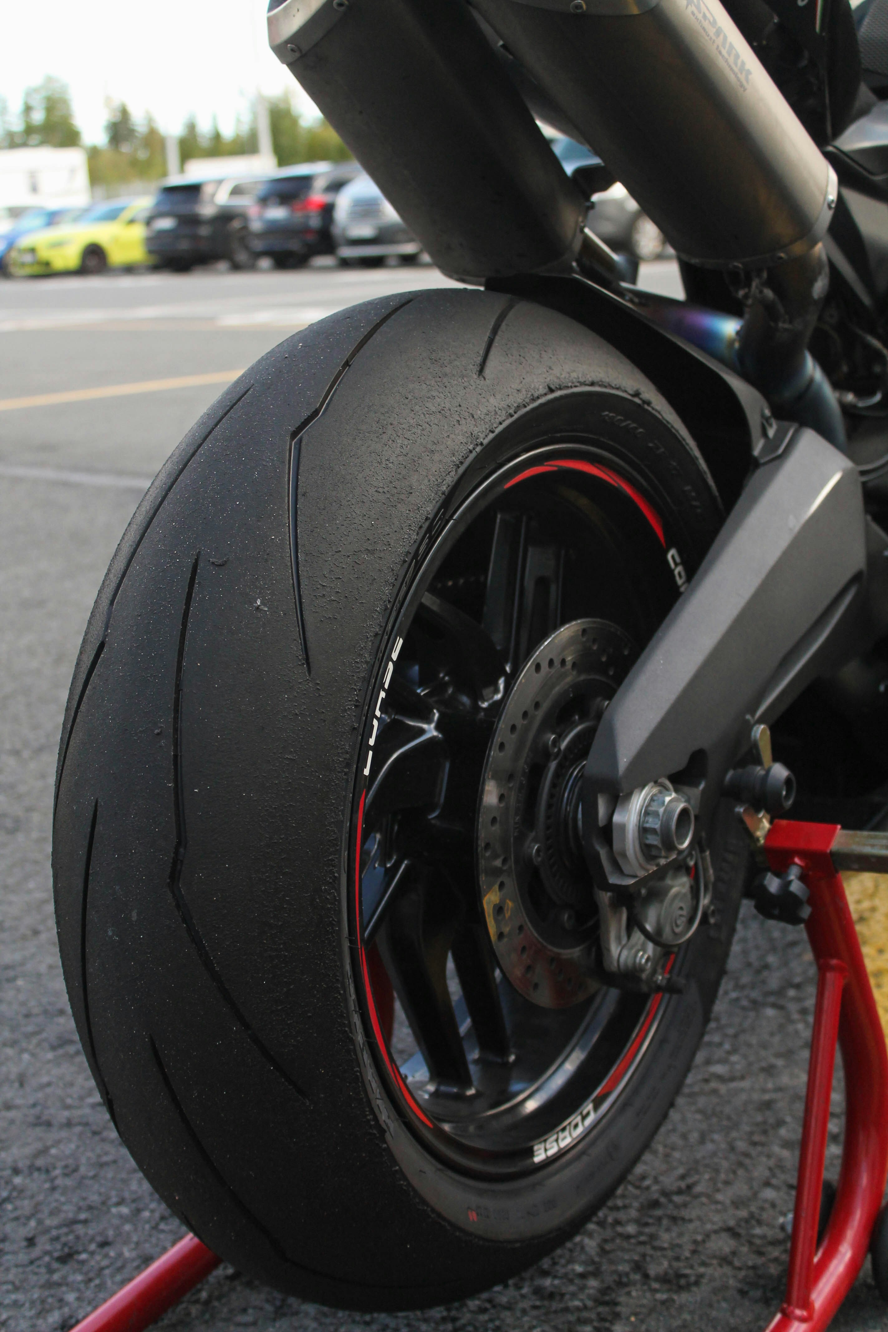 Close-up view of a motorcycle's rear tire showcasing intricate tread patterns and brake components. The image highlights the importance of tire design in racing performance.