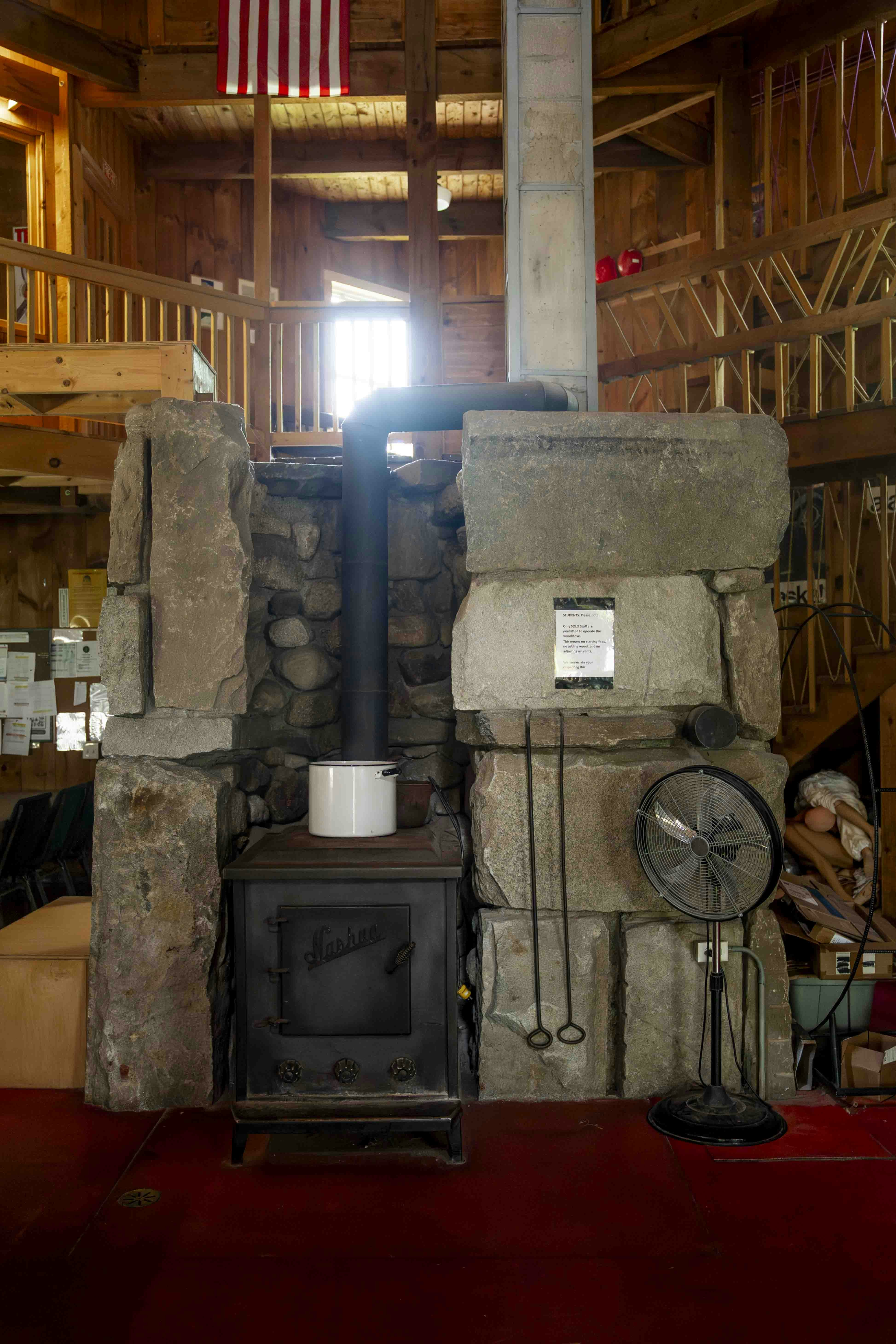 A vintage wood stove nestled within a stone hearth, surrounded by warm wooden interiors and a hint of nostalgia. The space evokes a cozy, inviting atmosphere.