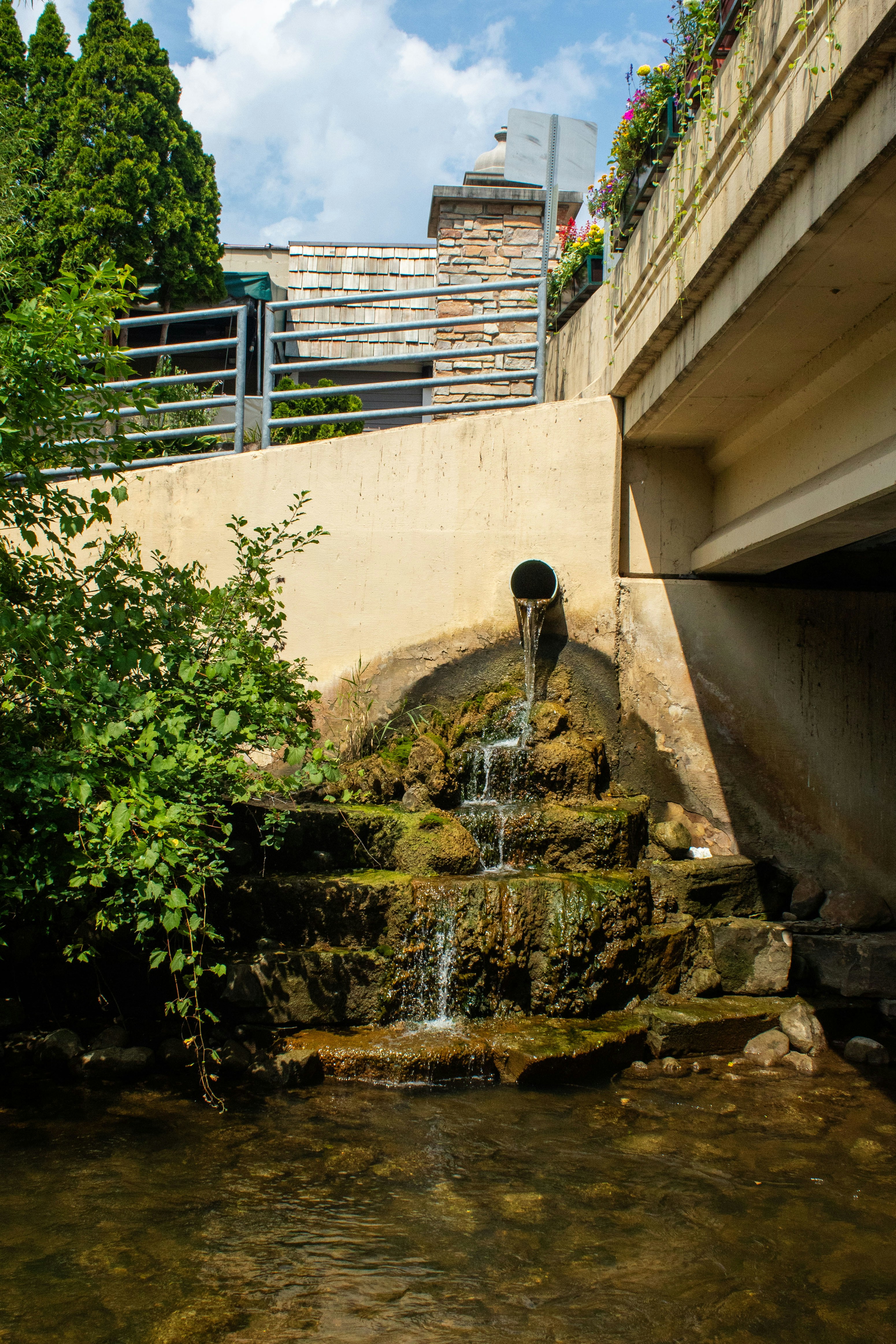 Water flows from a pipe over rocks into a stream.