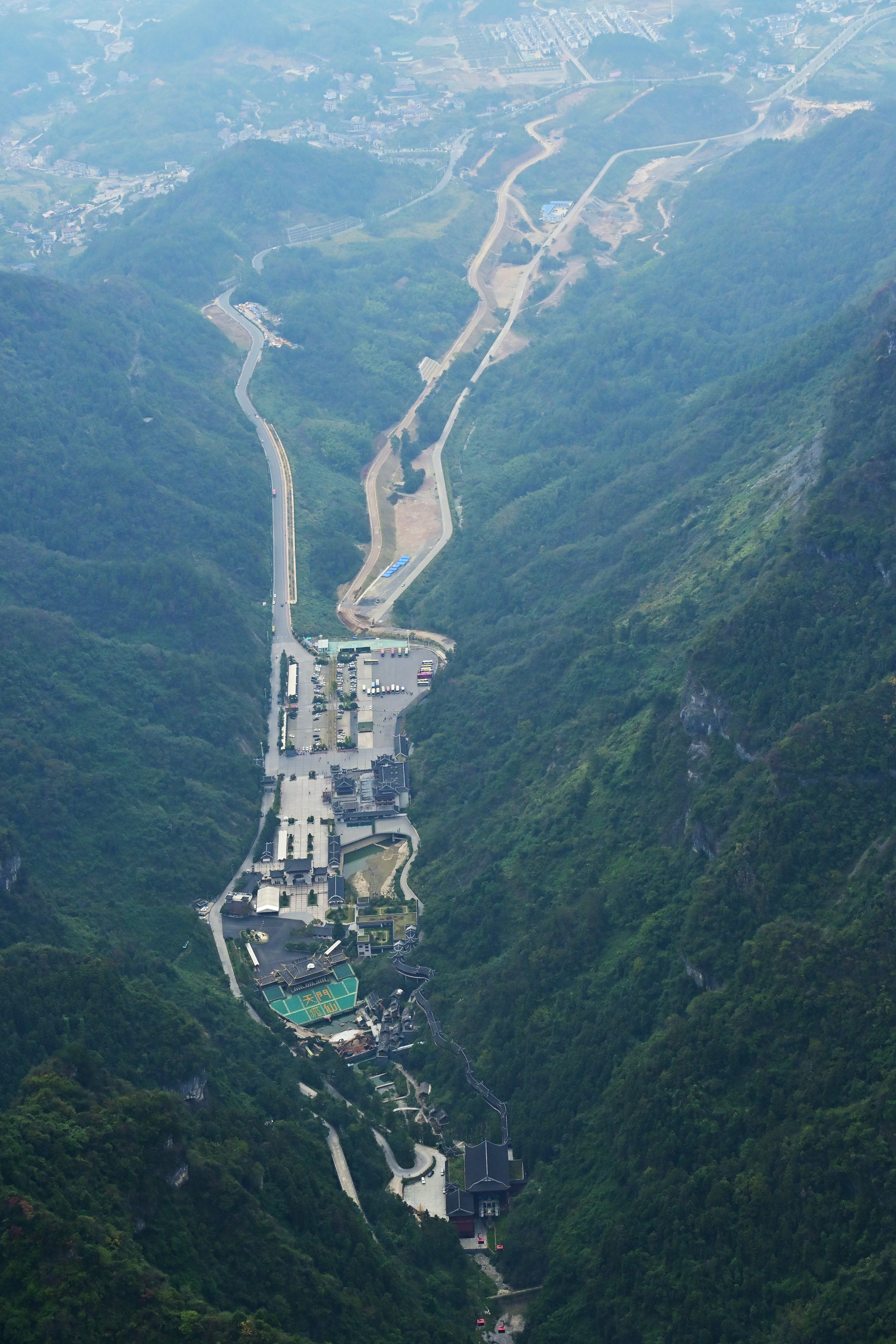 montain,road,highway | Aerial view of a winding road through a lush green mountain valley.