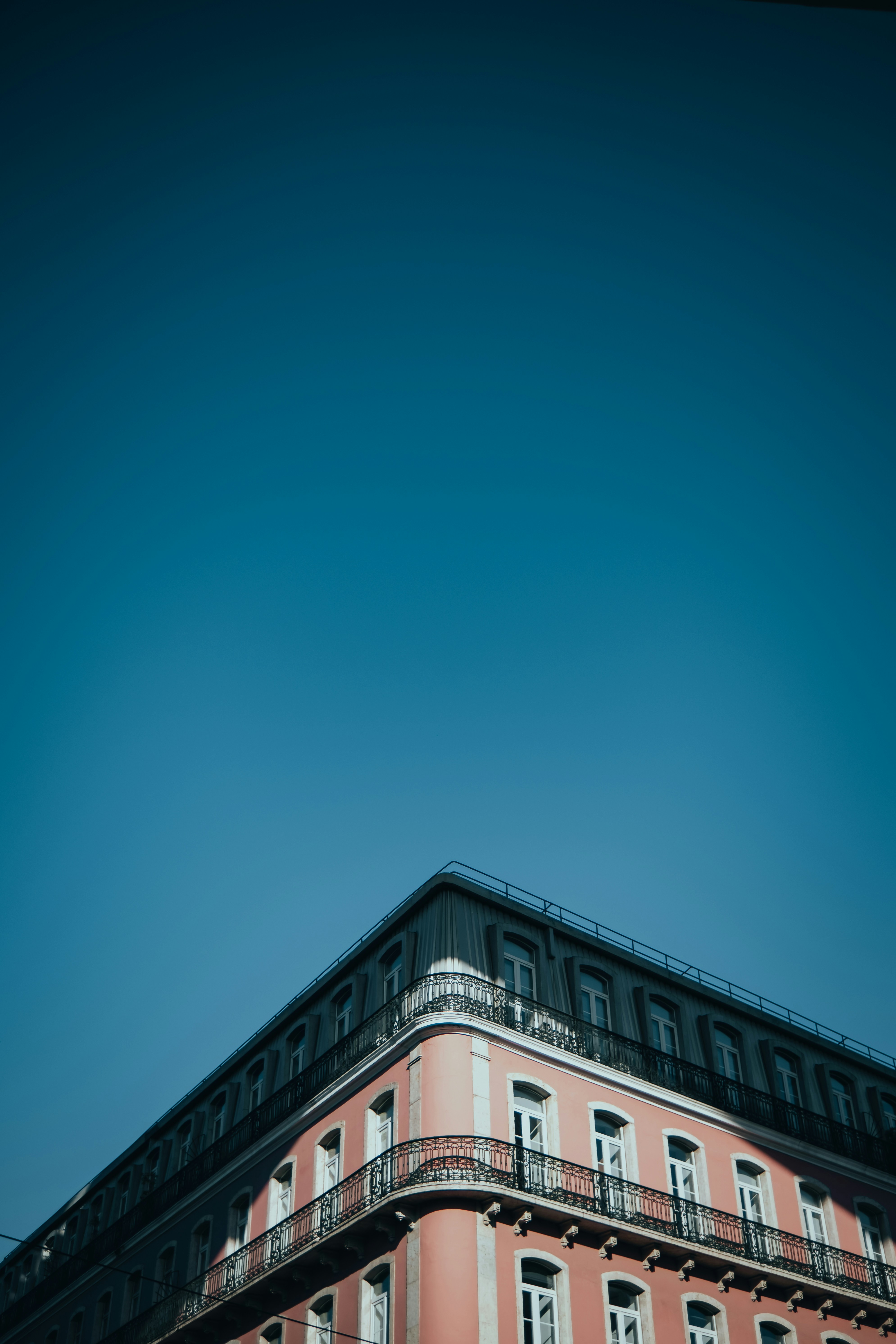 Corner of a pink building against a clear blue sky