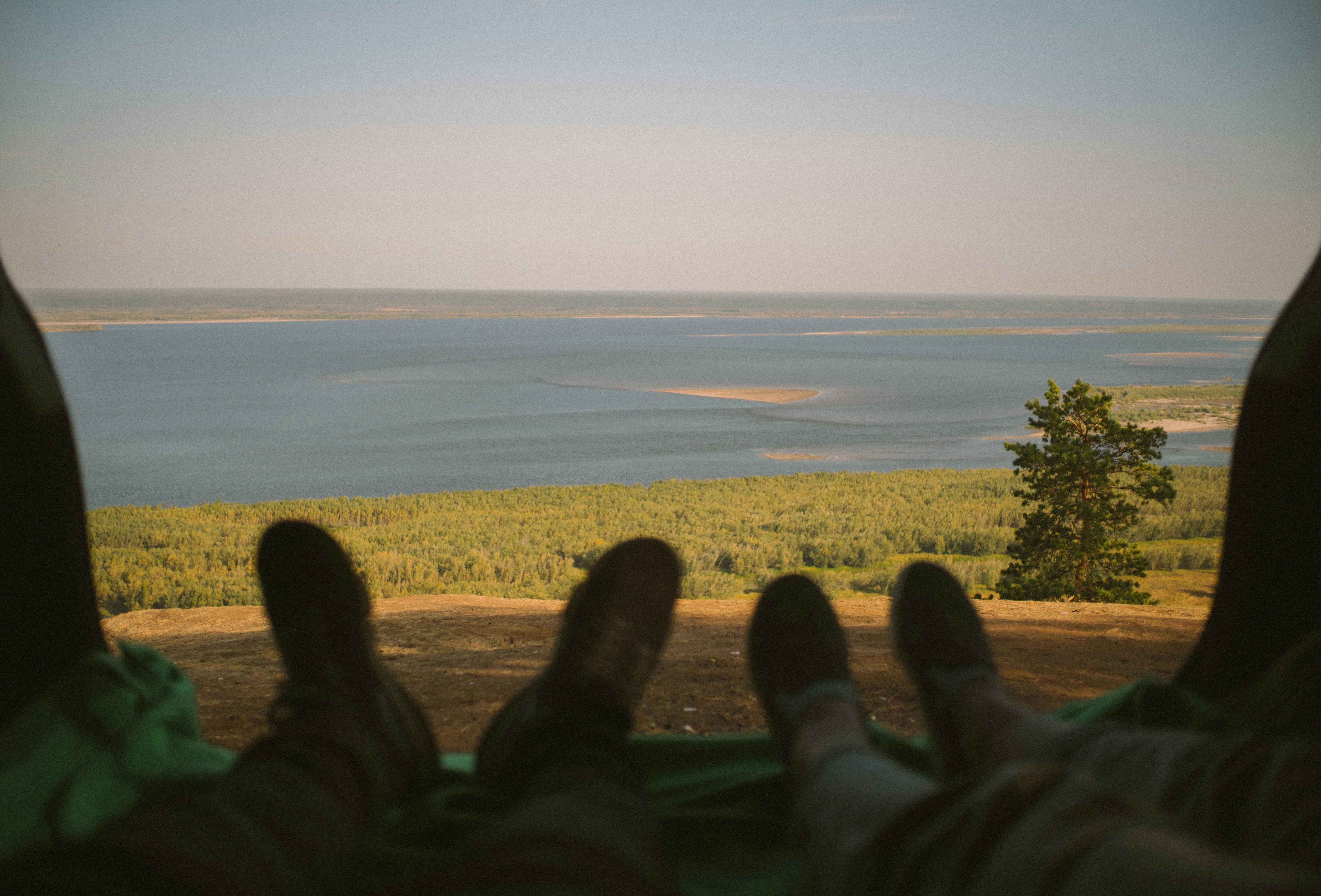 Two pairs of feet looking out at a serene lake view.