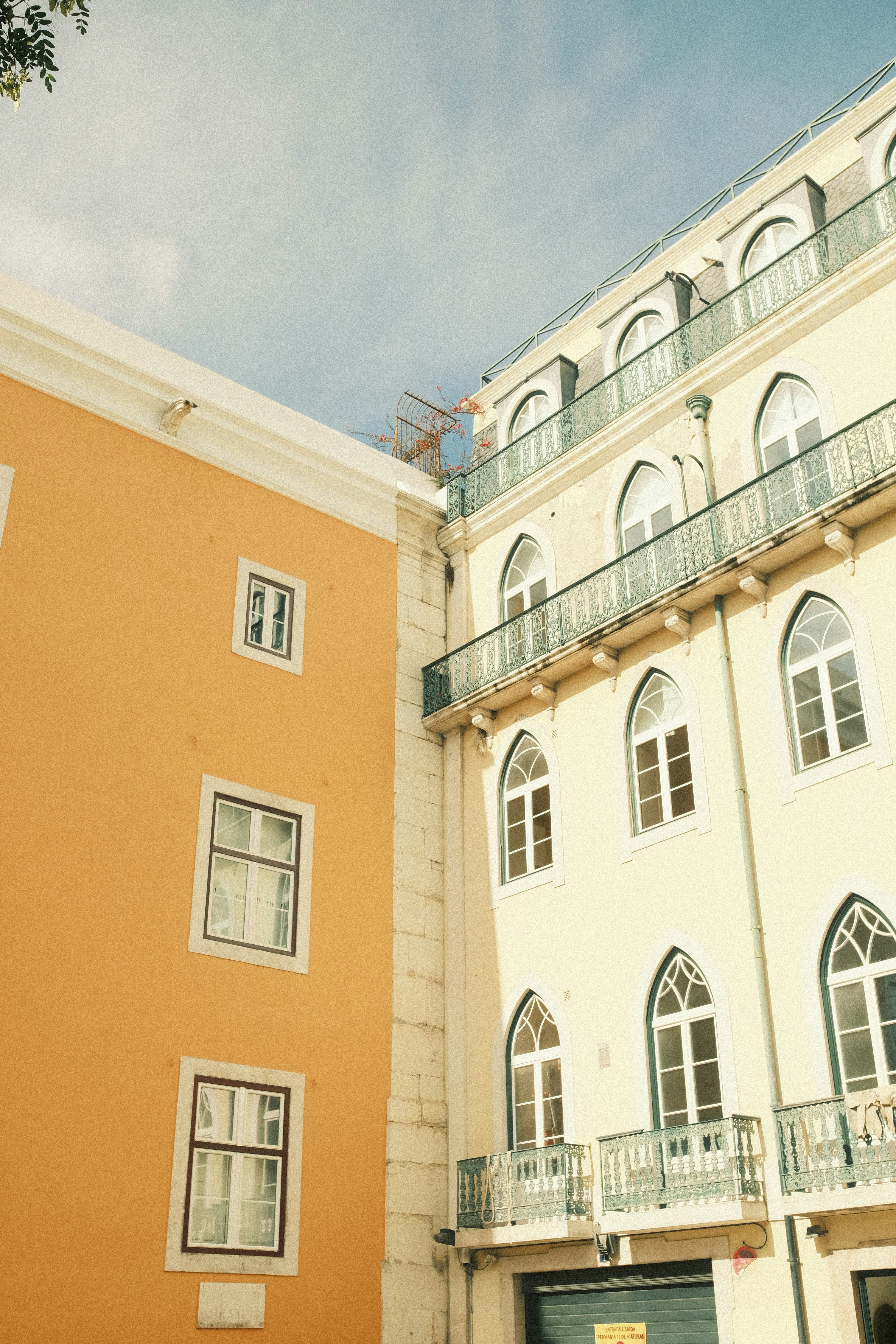 Cobblestone streets bathed in warm sunlight, lined with pastel European buildings and classic balconies. Perfect for urban, travel, and lifestyle visuals. | Two historic buildings with arched windows under sky