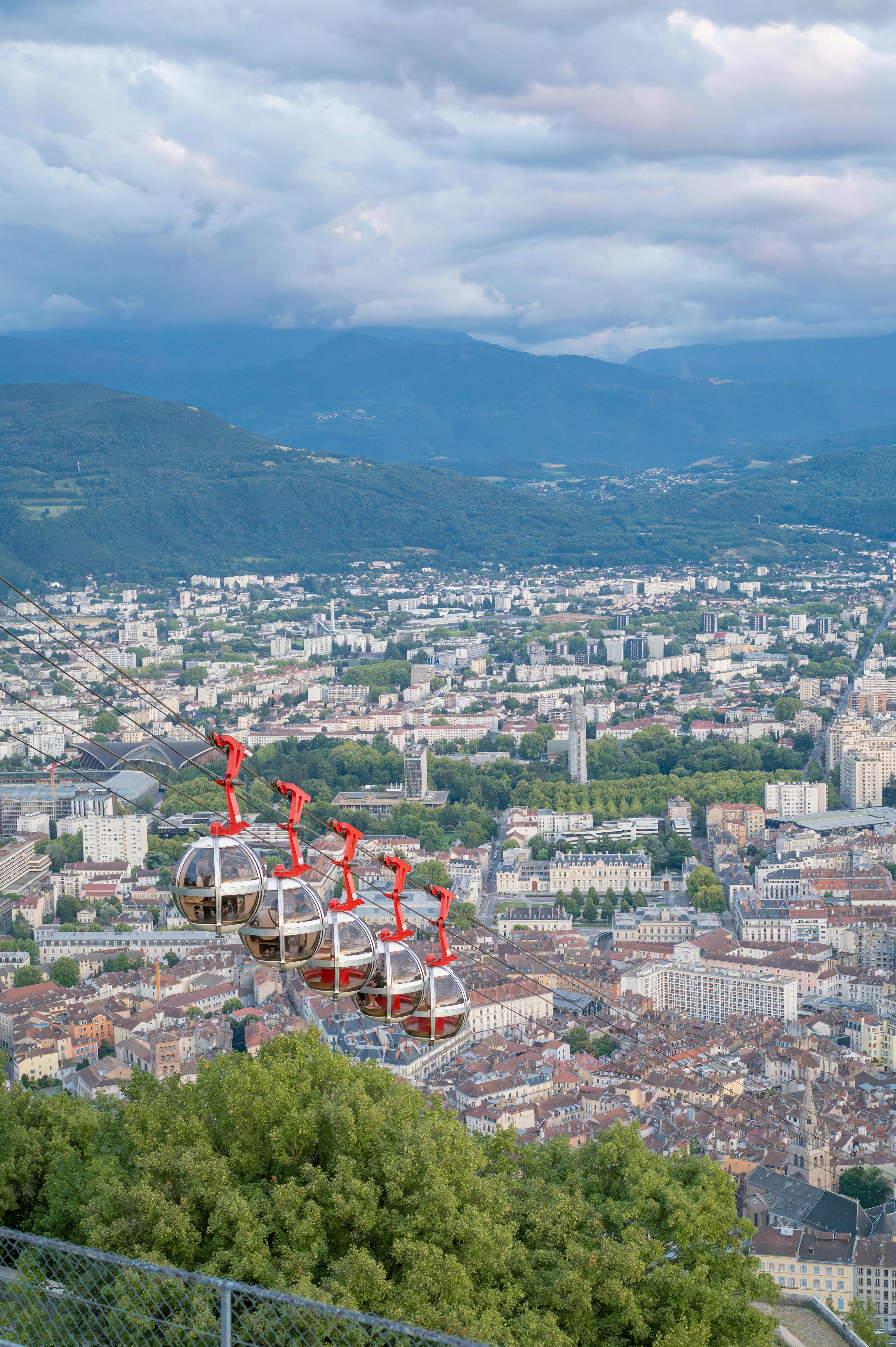 Red Gondola Row Over a Mountain-Framed Cityscape