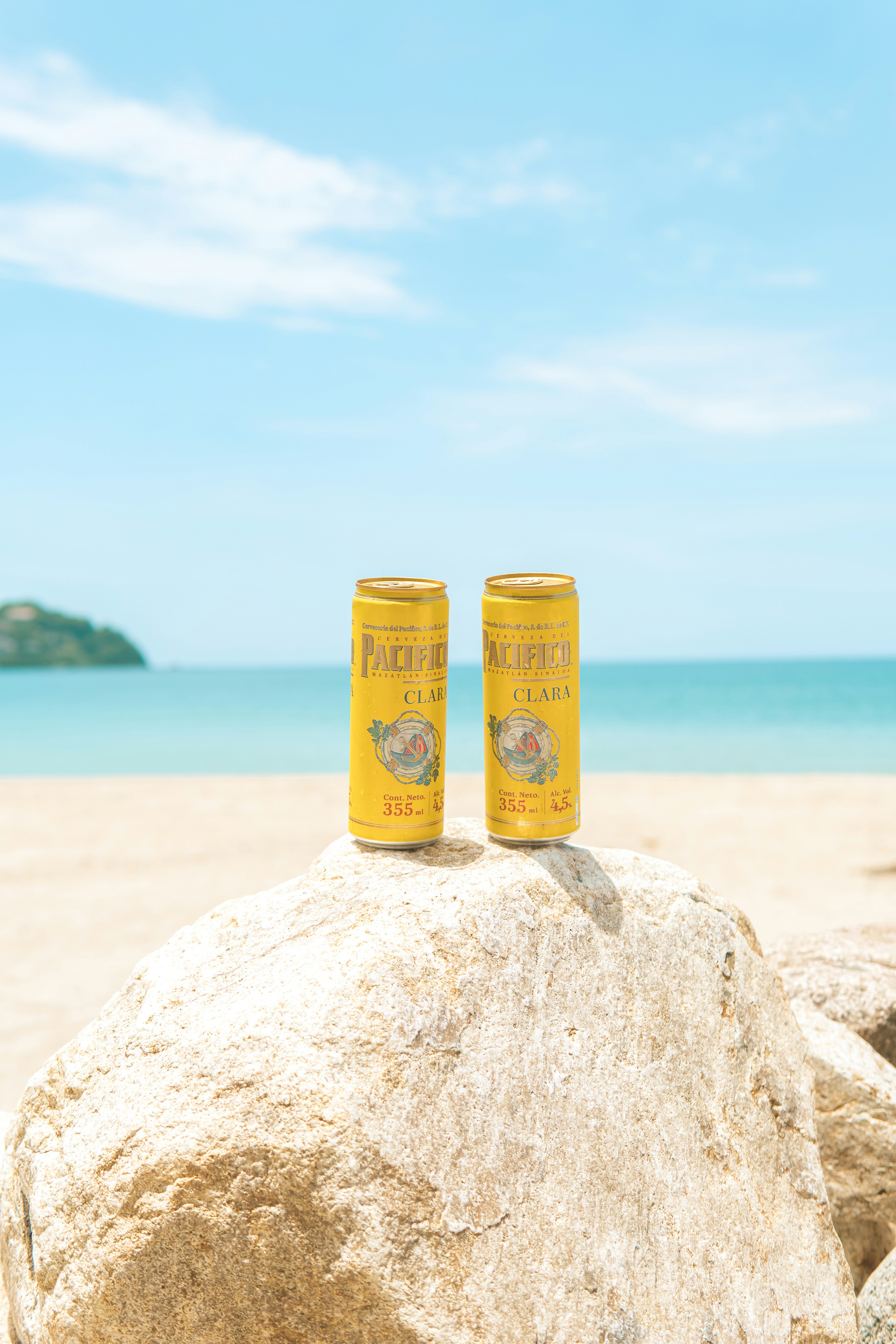 Two yellow cans on a rock at the beach.