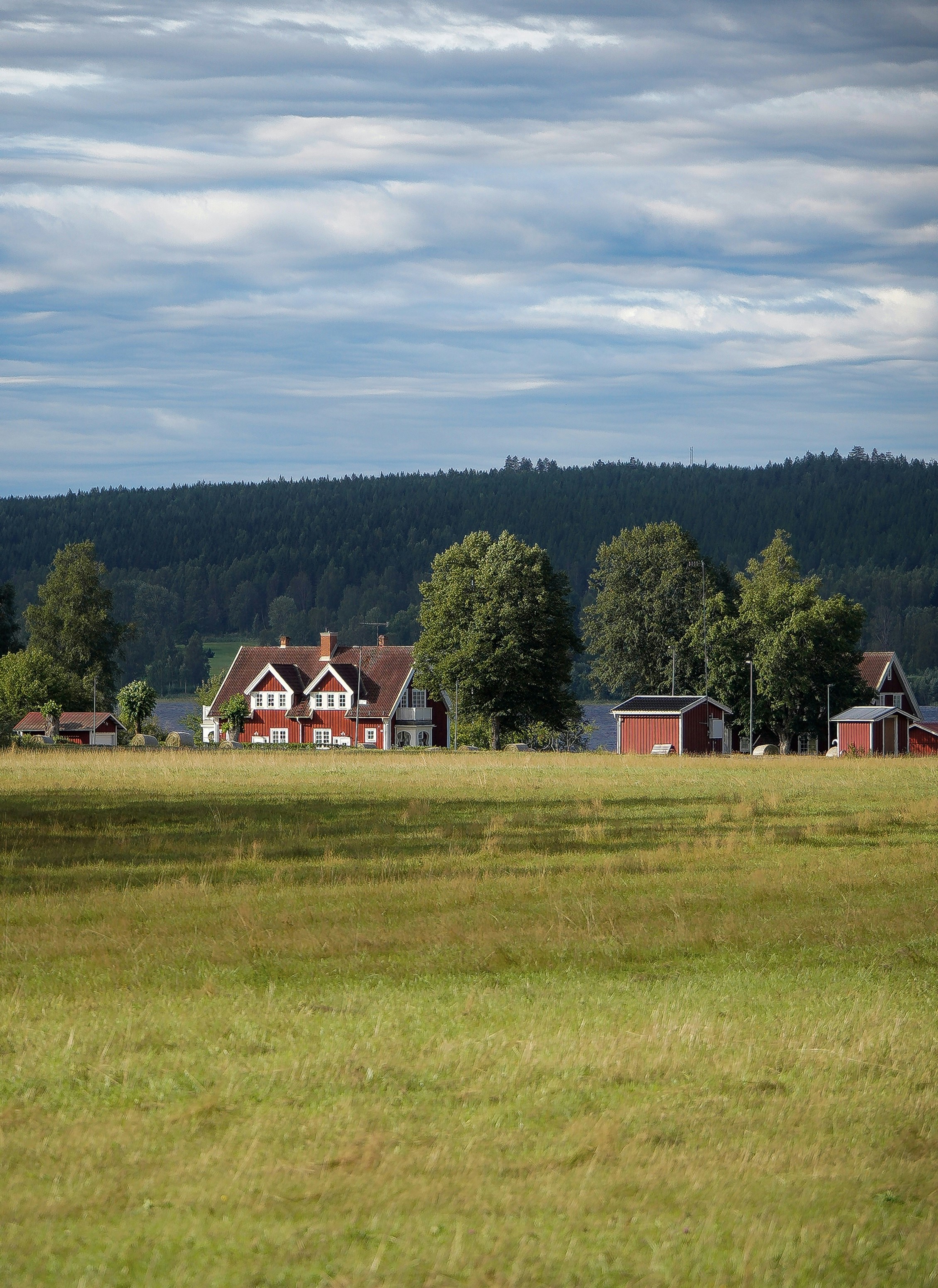 Red farmhouse with outbuildings in a grassy field.