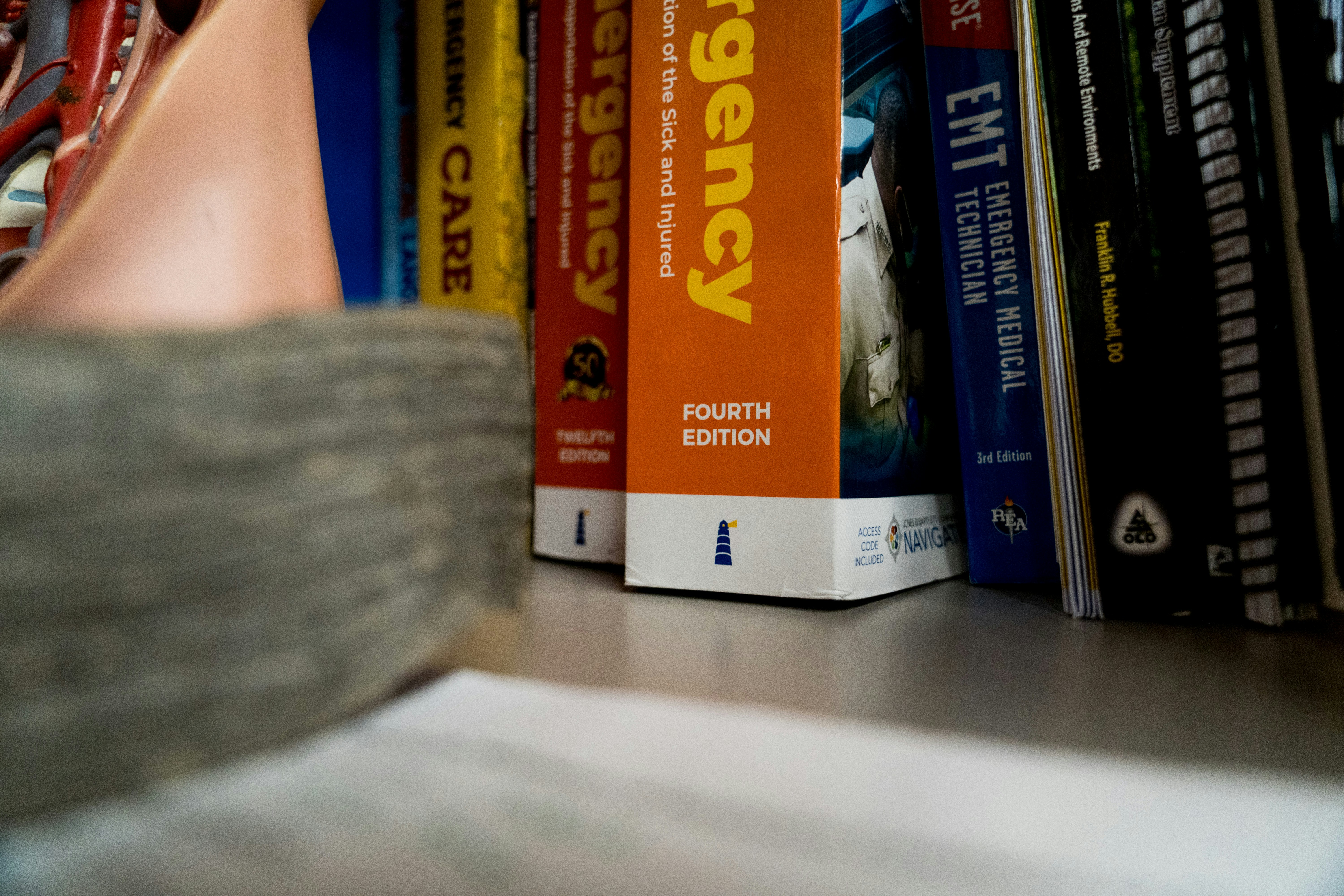 Close-up of medical textbooks and a shoe, highlighting essential resources for emergency response training.