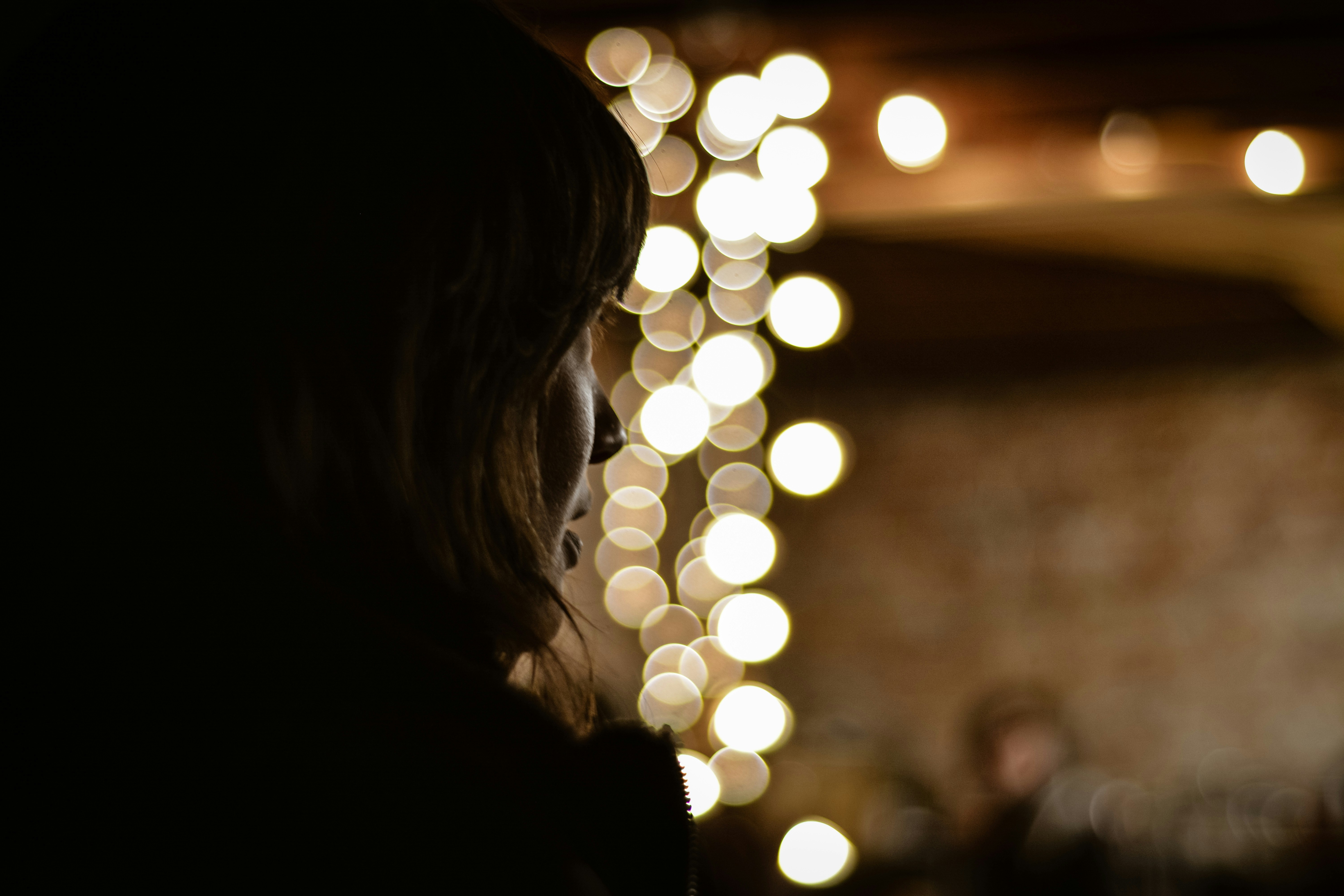 Silhouette of a woman against a backdrop of softly glowing bokeh lights, creating a serene atmosphere.