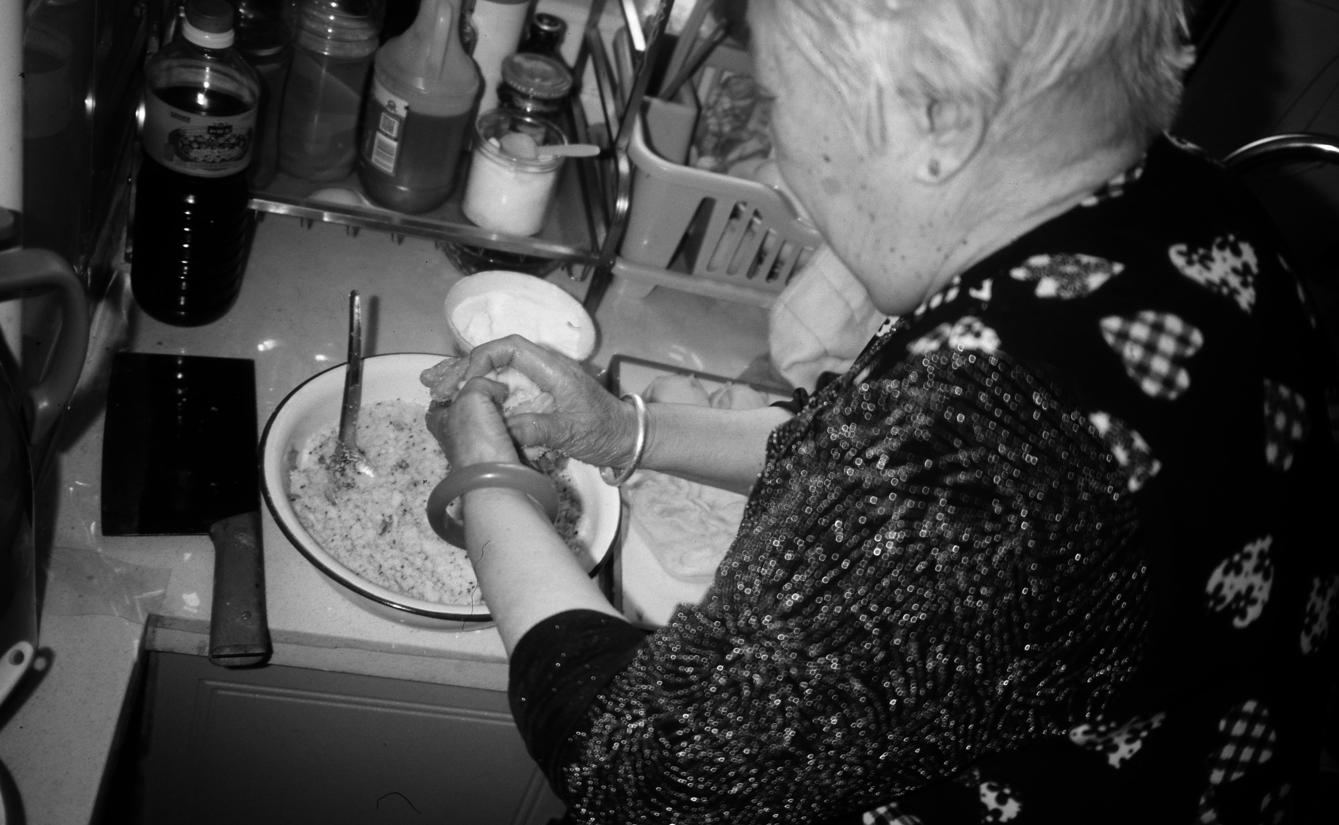 My grandmother used to work at a food processing unit making pastries when she was young. Nowadays, she occasionally puts her old skills to use at home — after all, homemade treats just taste better than store-bought ones. | Elderly person preparing food in a kitchen.