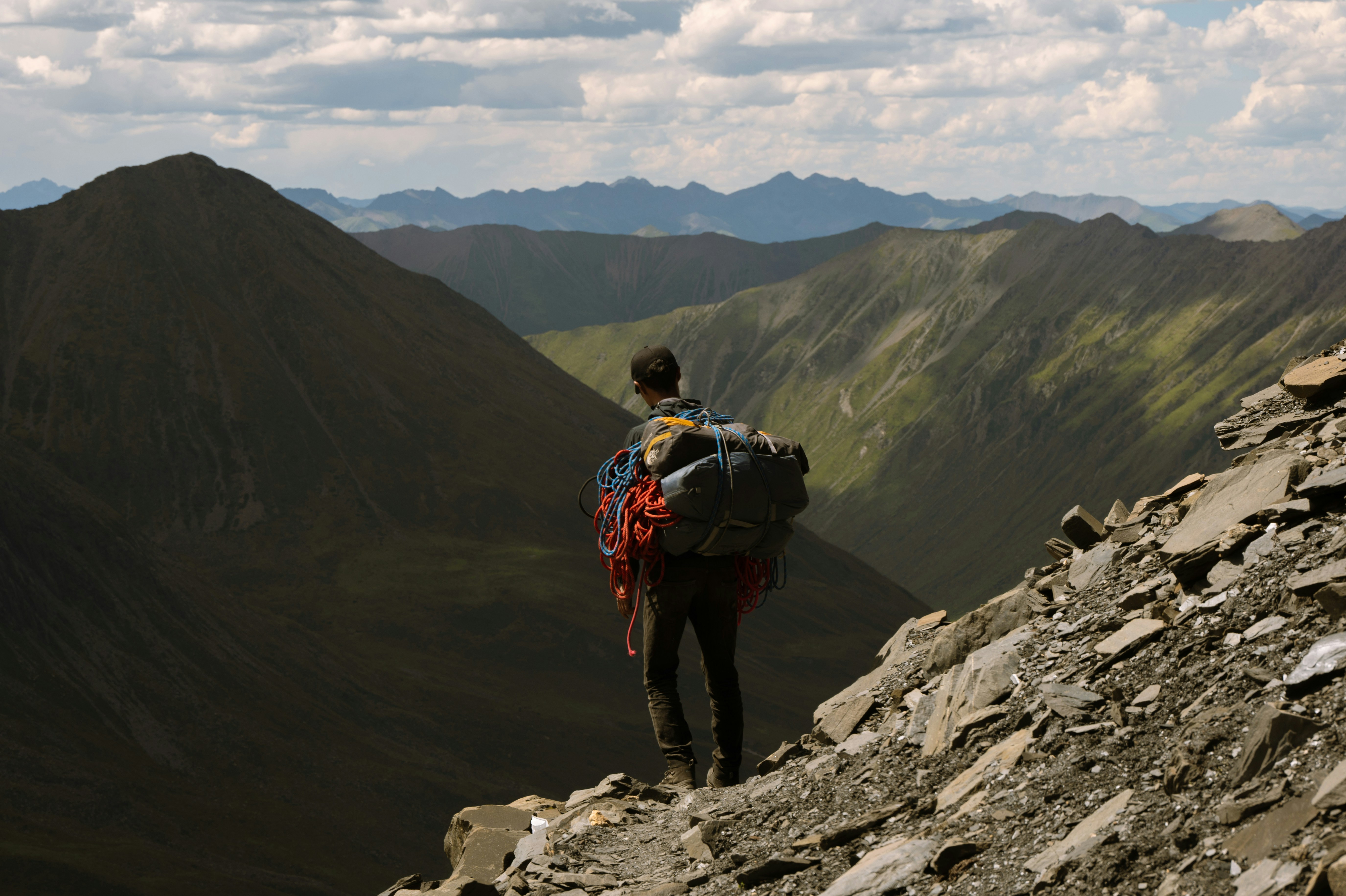 A lonely mountain climber. | Hiker with backpack on rocky mountain trail
