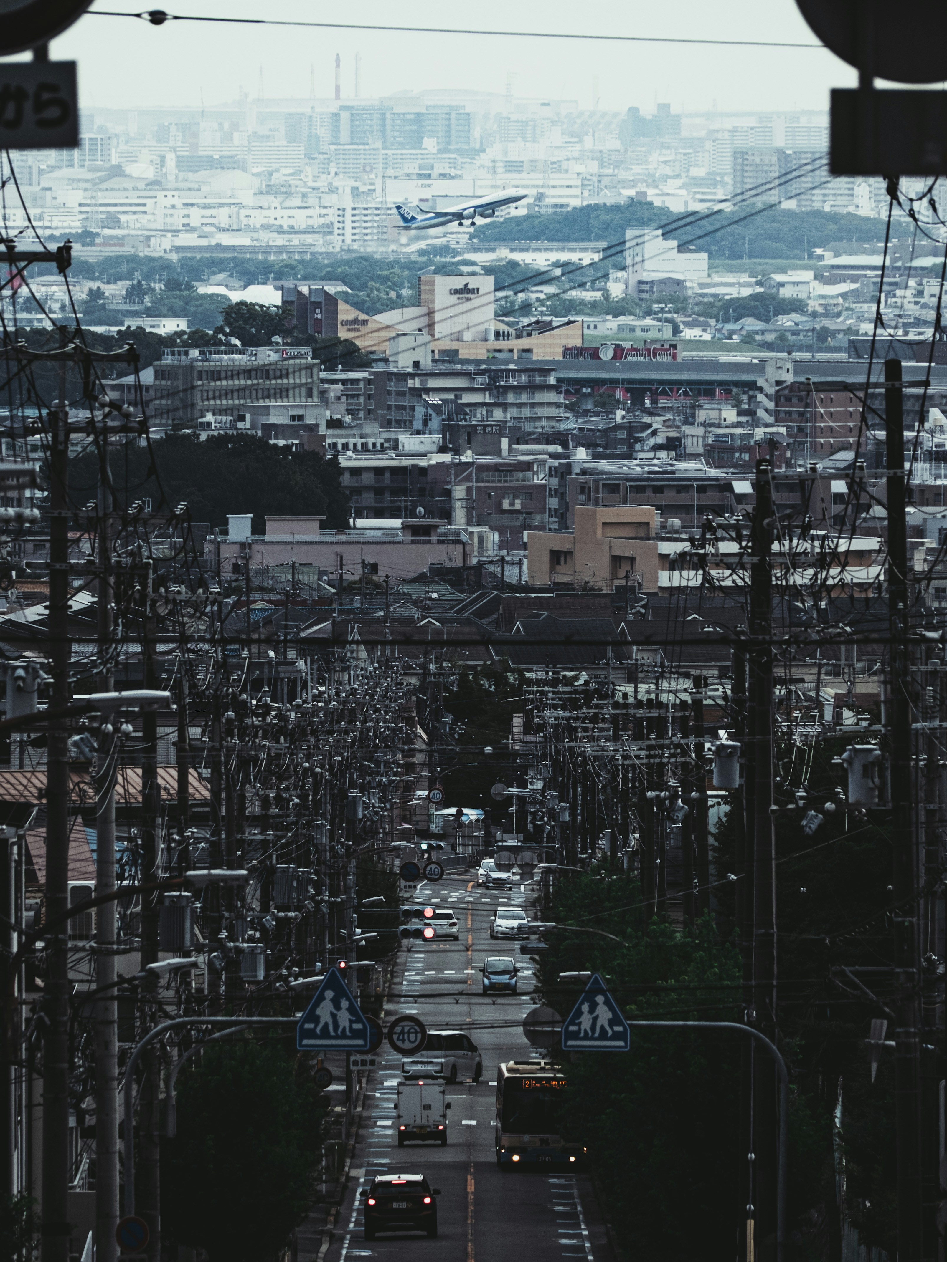 City street with power lines and distant airplane
