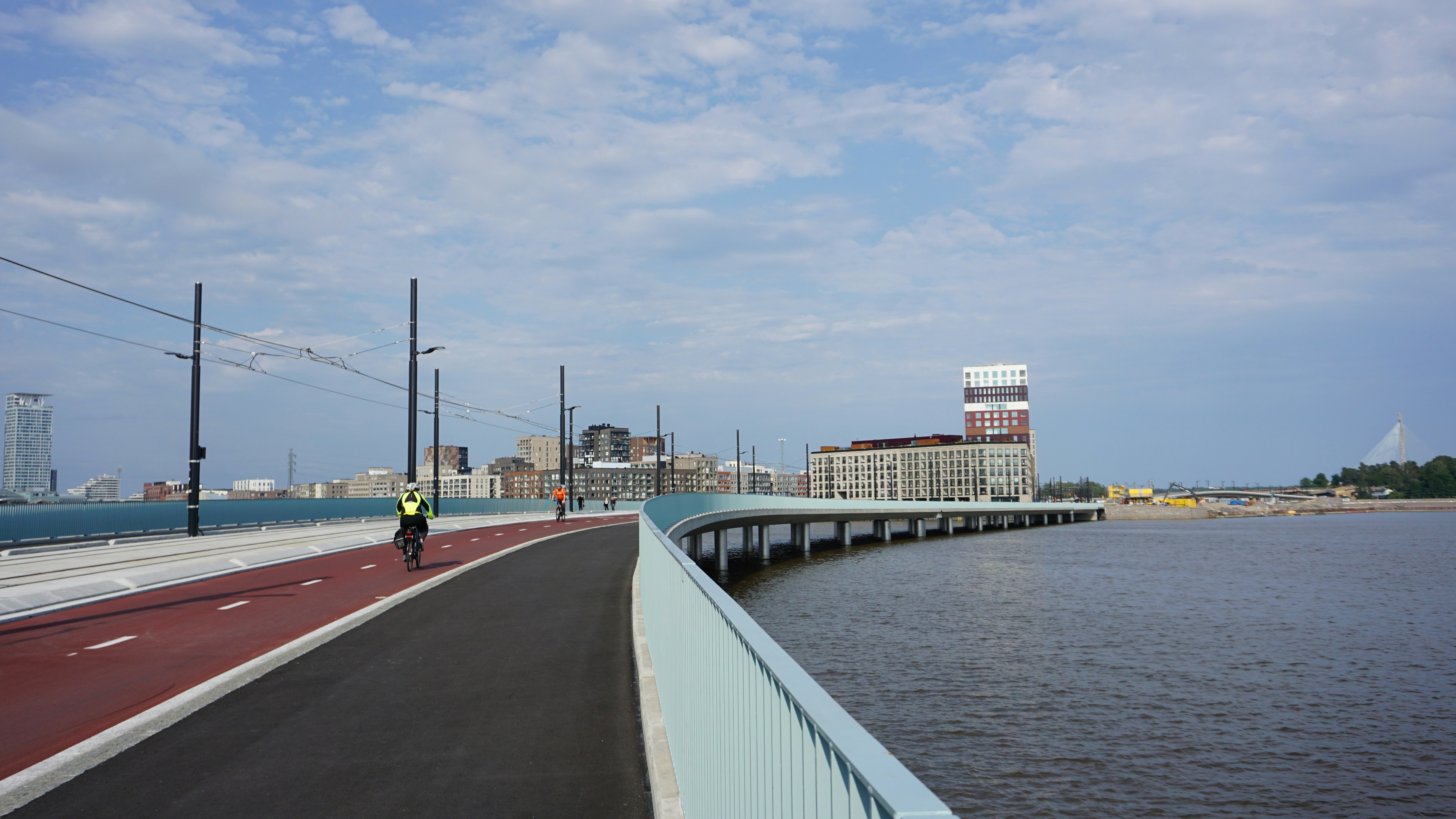 Cyclist on a modern bridge over water with cityscape