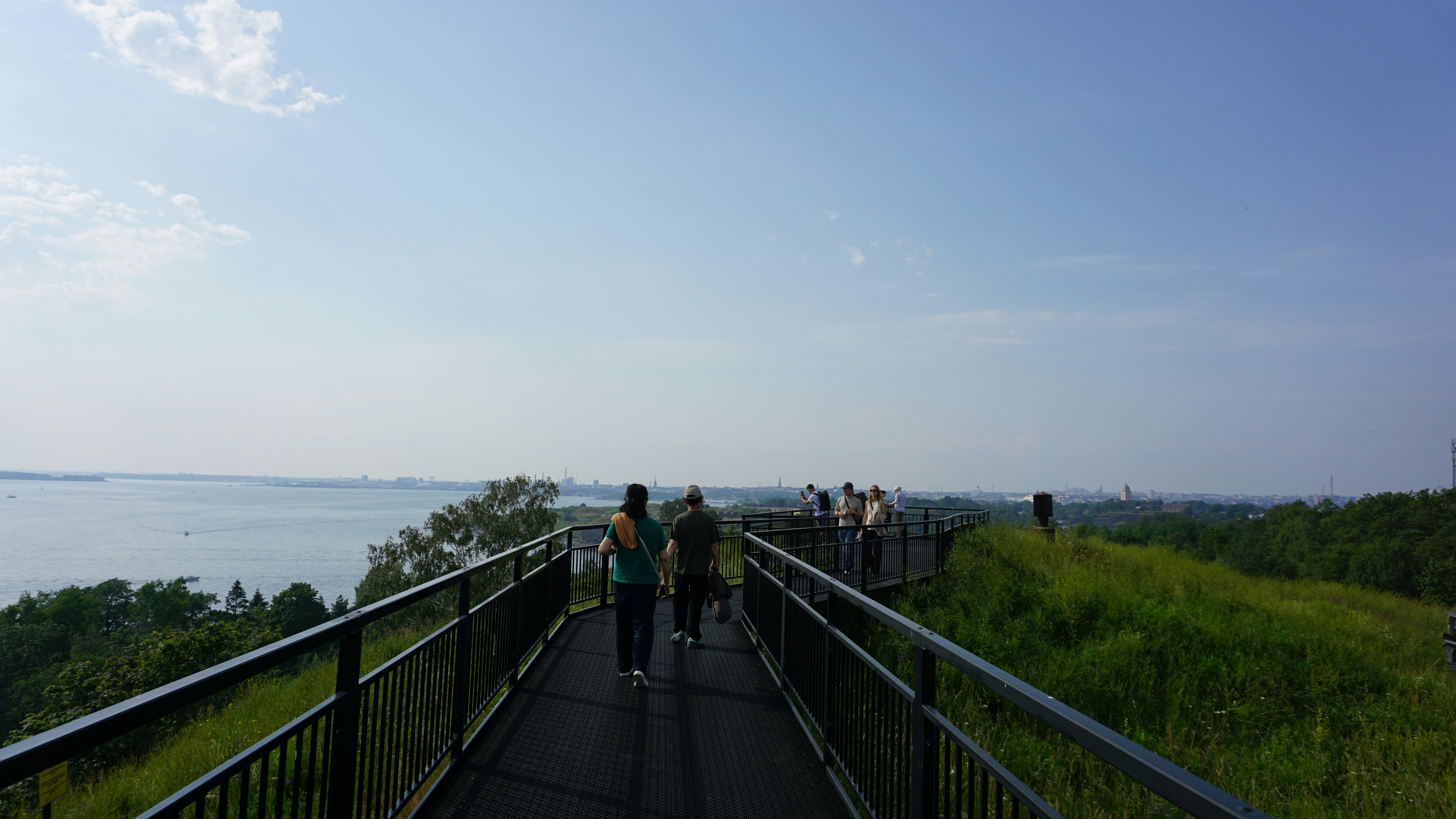 People walking on a path overlooking a calm blue lake. photo – Free ...