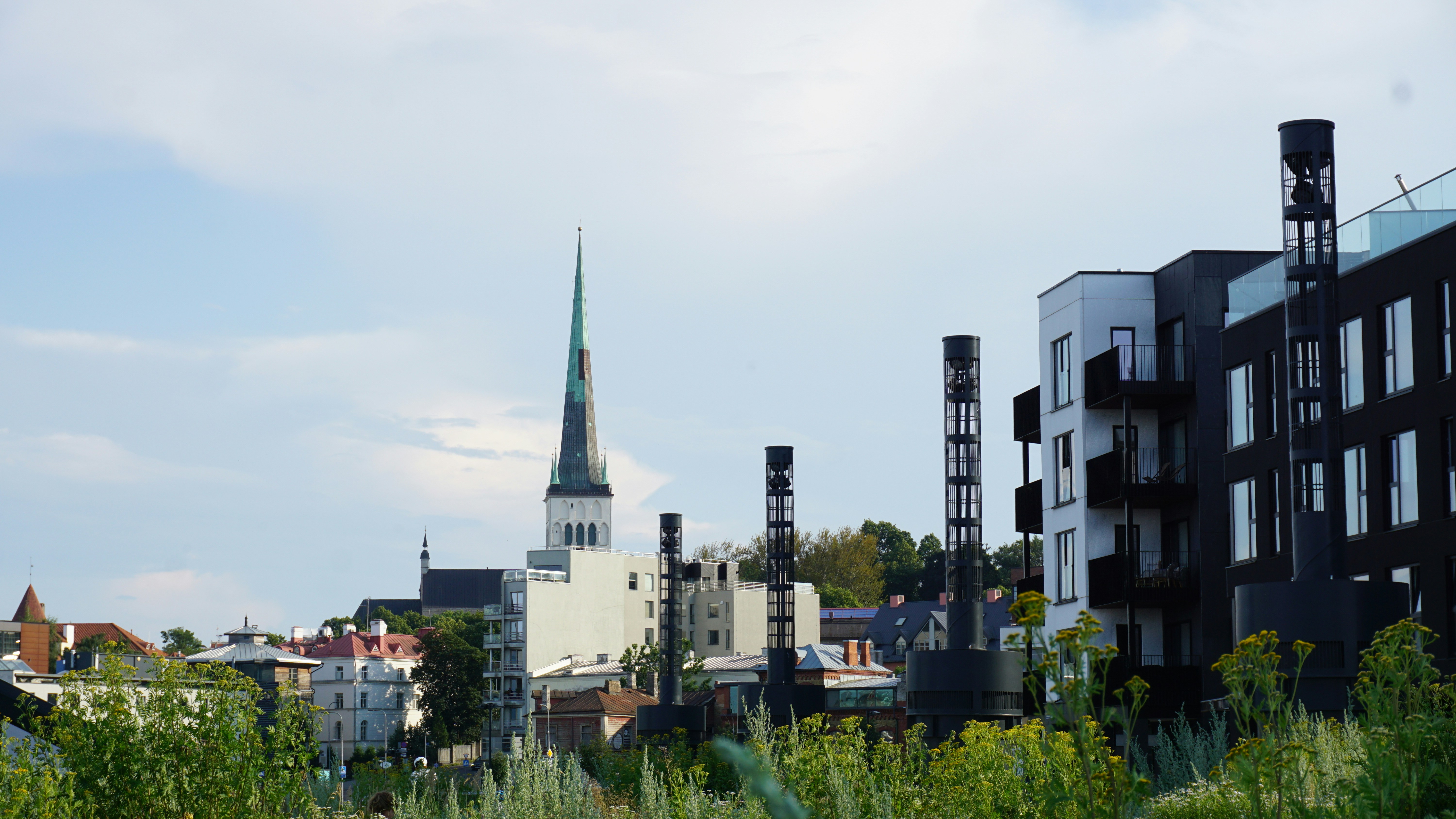 Modern buildings and a church spire under a cloudy sky