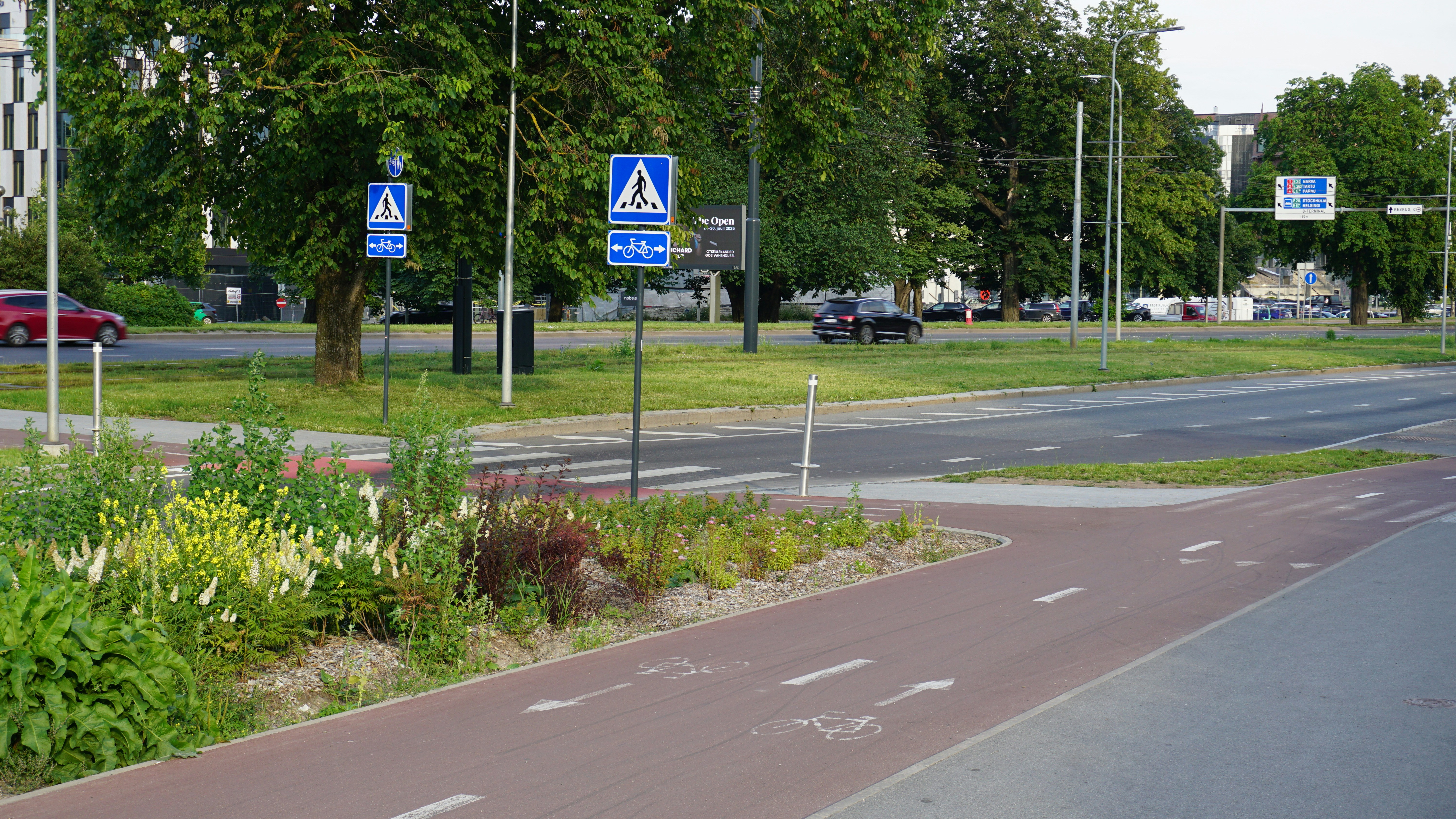 Bicycle path bordered by vibrant flowers and signage in a modern urban setting. The scene illustrates a blend of nature and city planning.