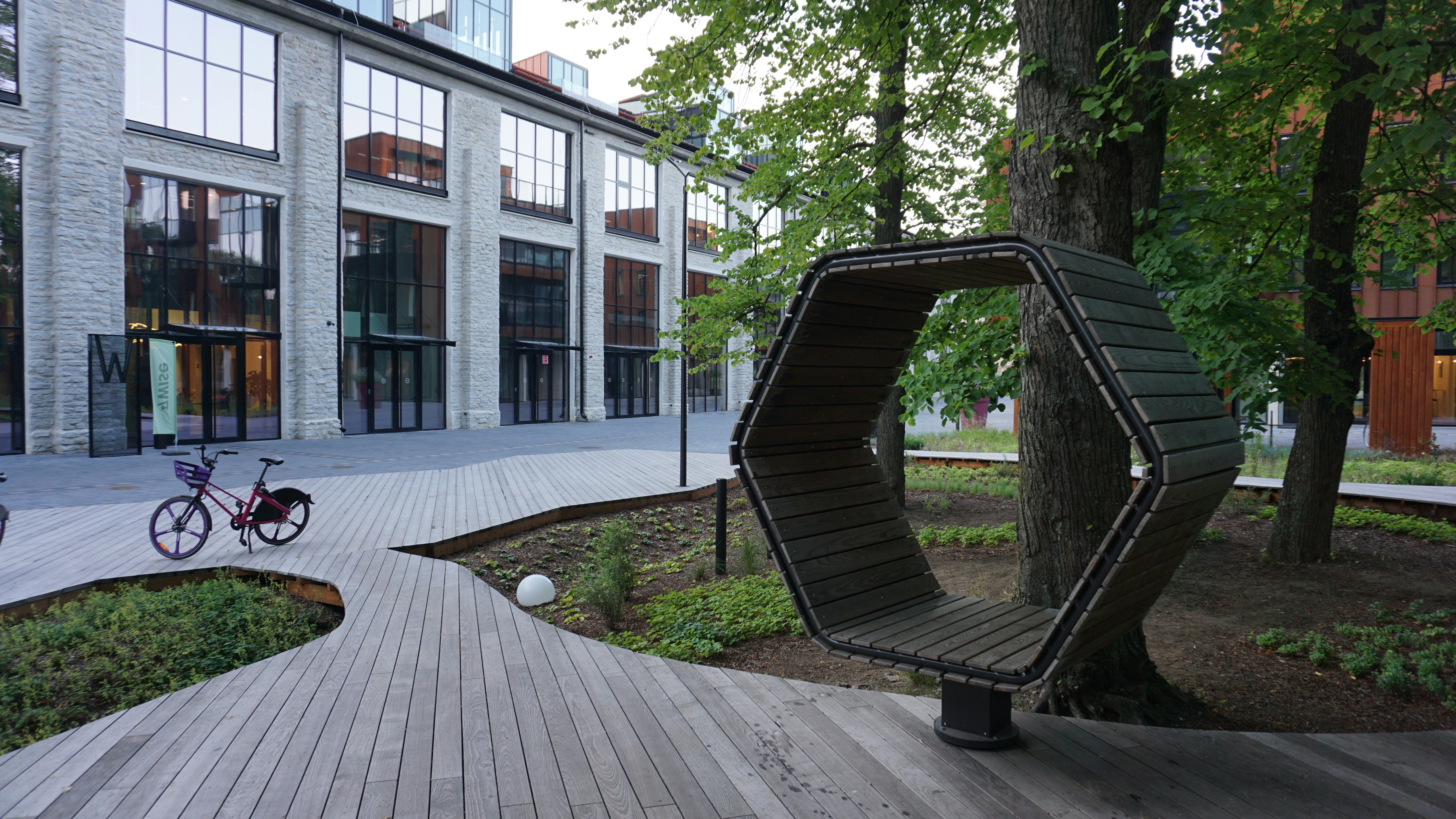 Modern park bench with wooden walkway and building