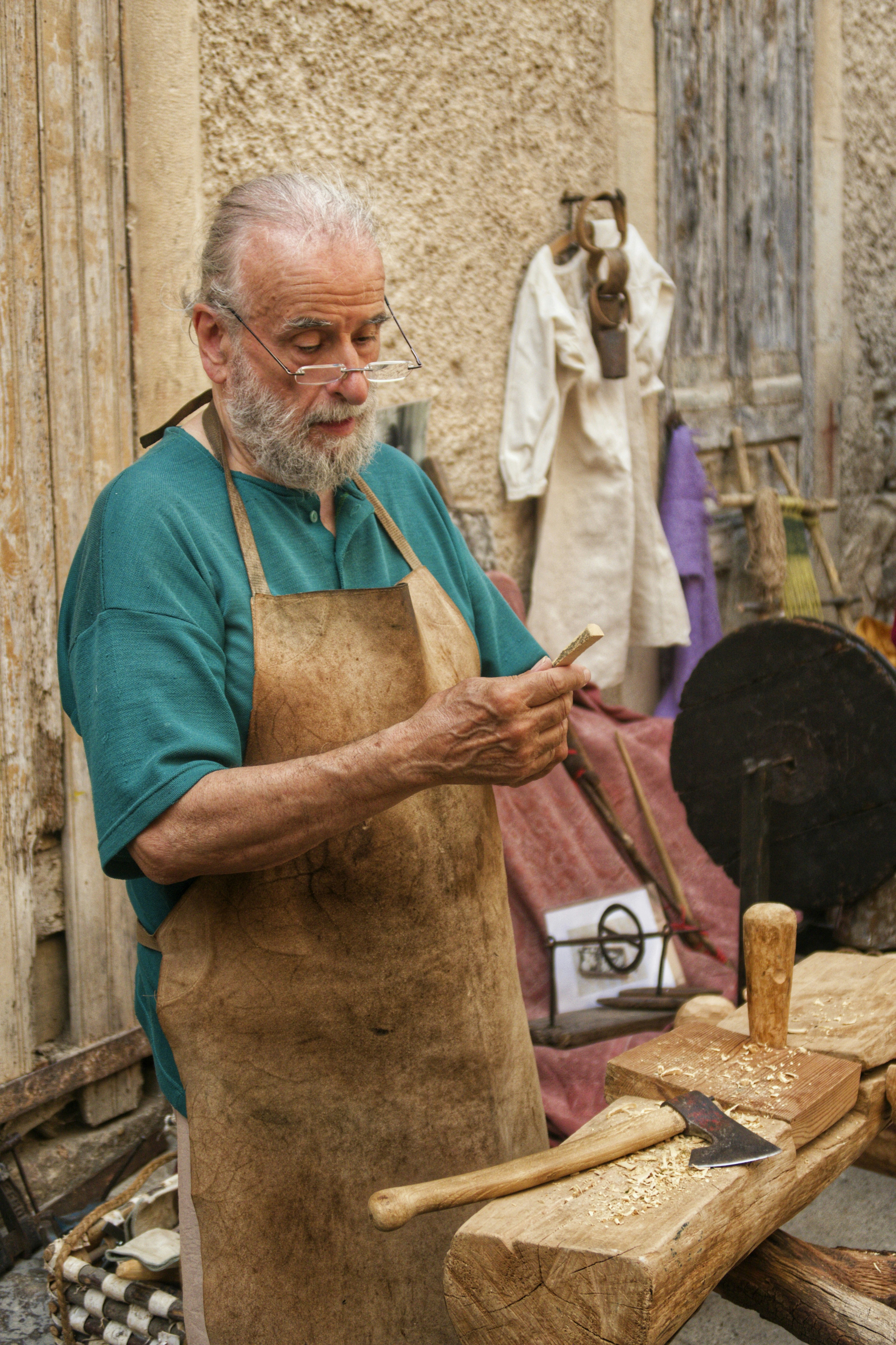 Elderly man carving wood with tools